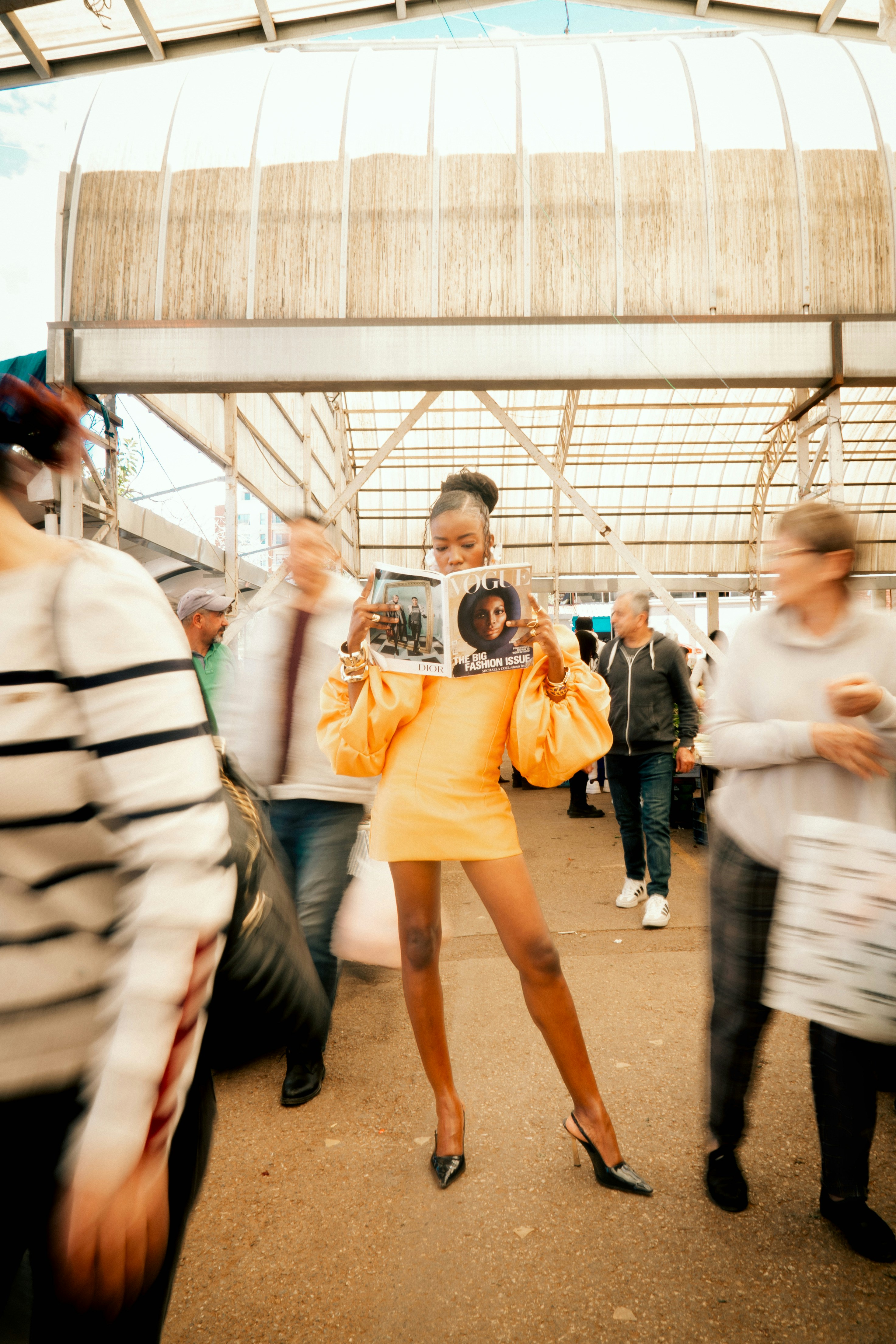 City Street Muse: A Model in Orange Holds Court with a Fashion Magazine