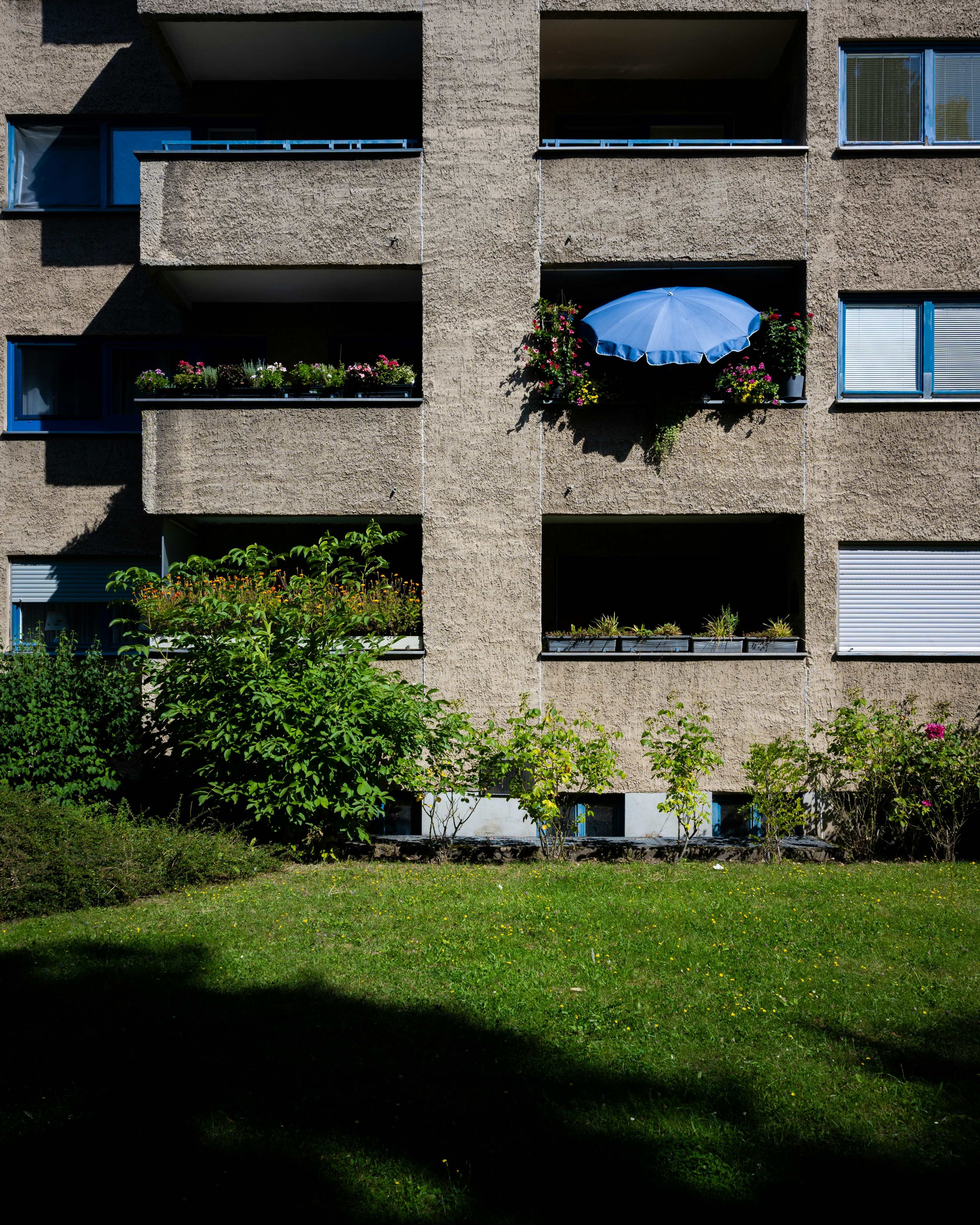 Blue Parasol on Balcony: A Quiet Moment of Color Amid Concrete
