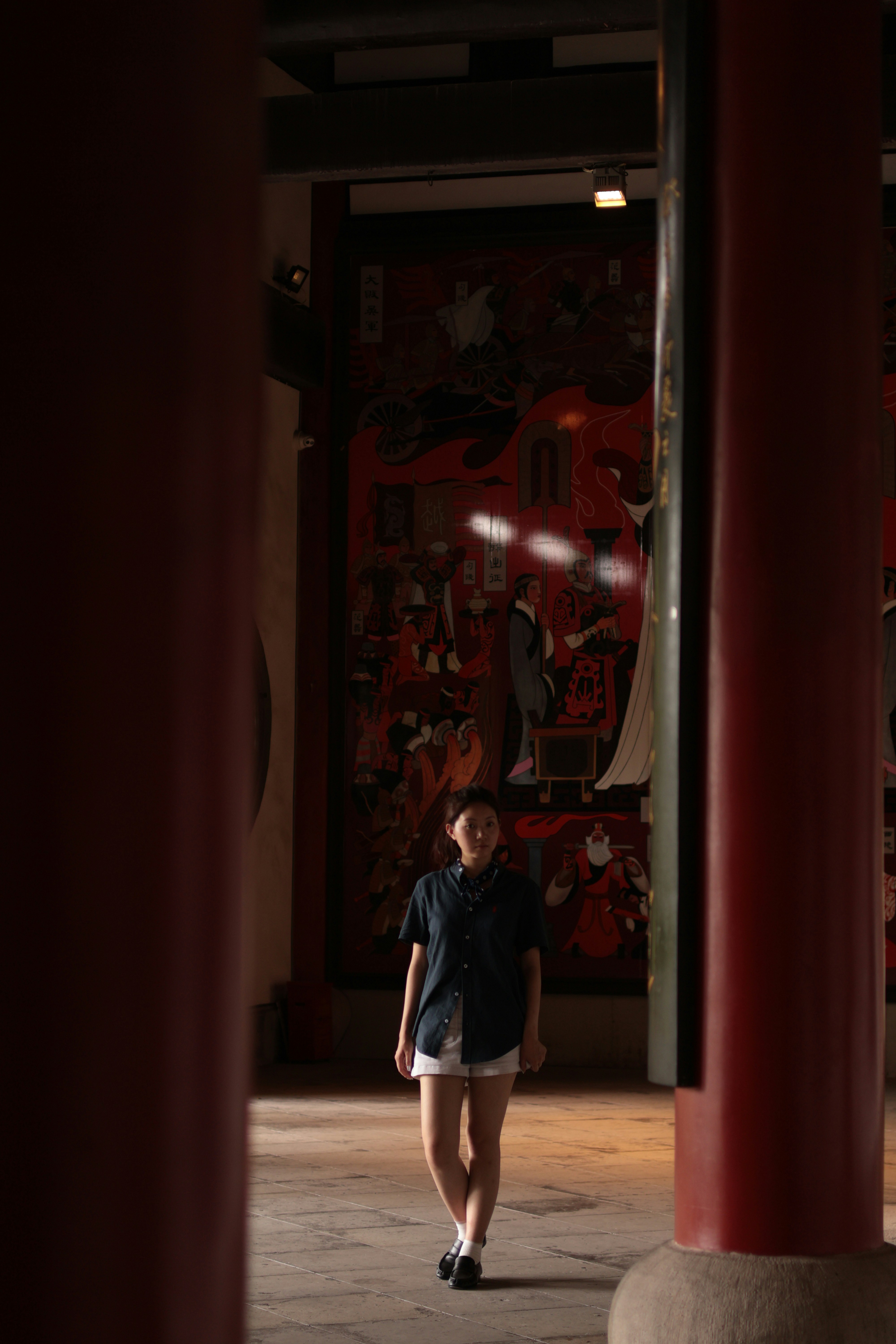 Into the Dim Corridor: A lone figure in a temple alcove