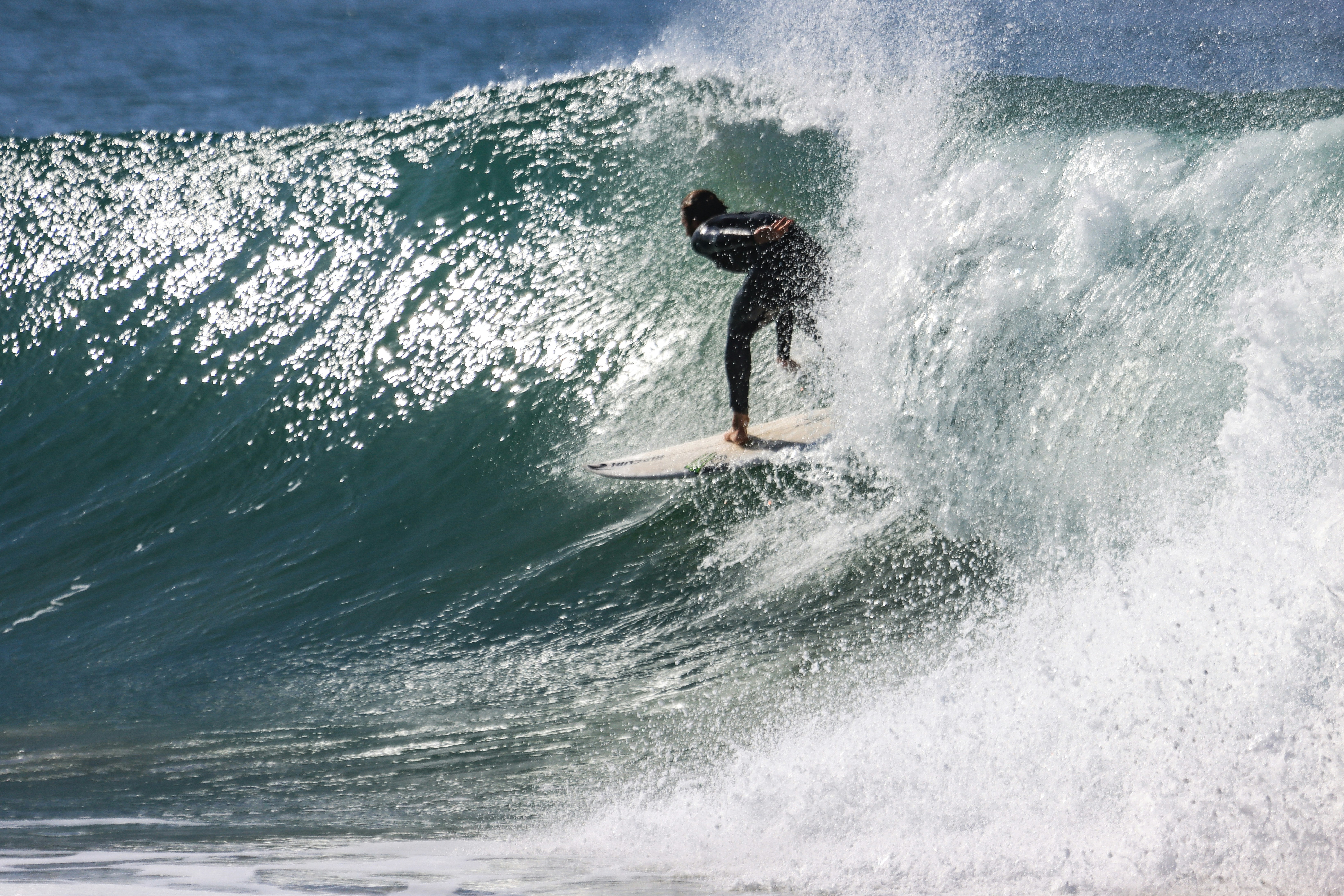 A person in a black wetsuit surfing a large breaking wave