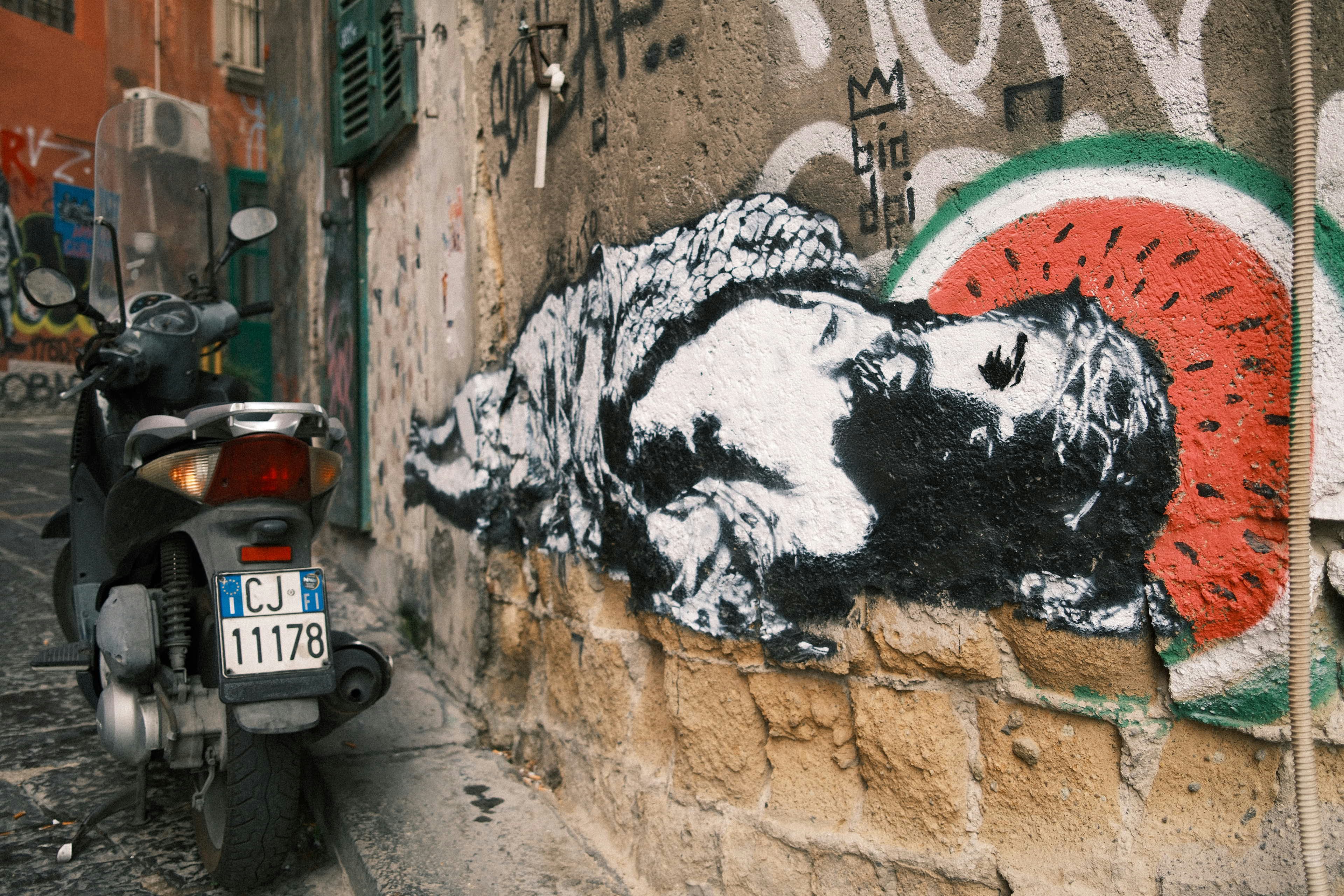 Graffiti Portrait on Narrow Street: A Street Study with a Scooter