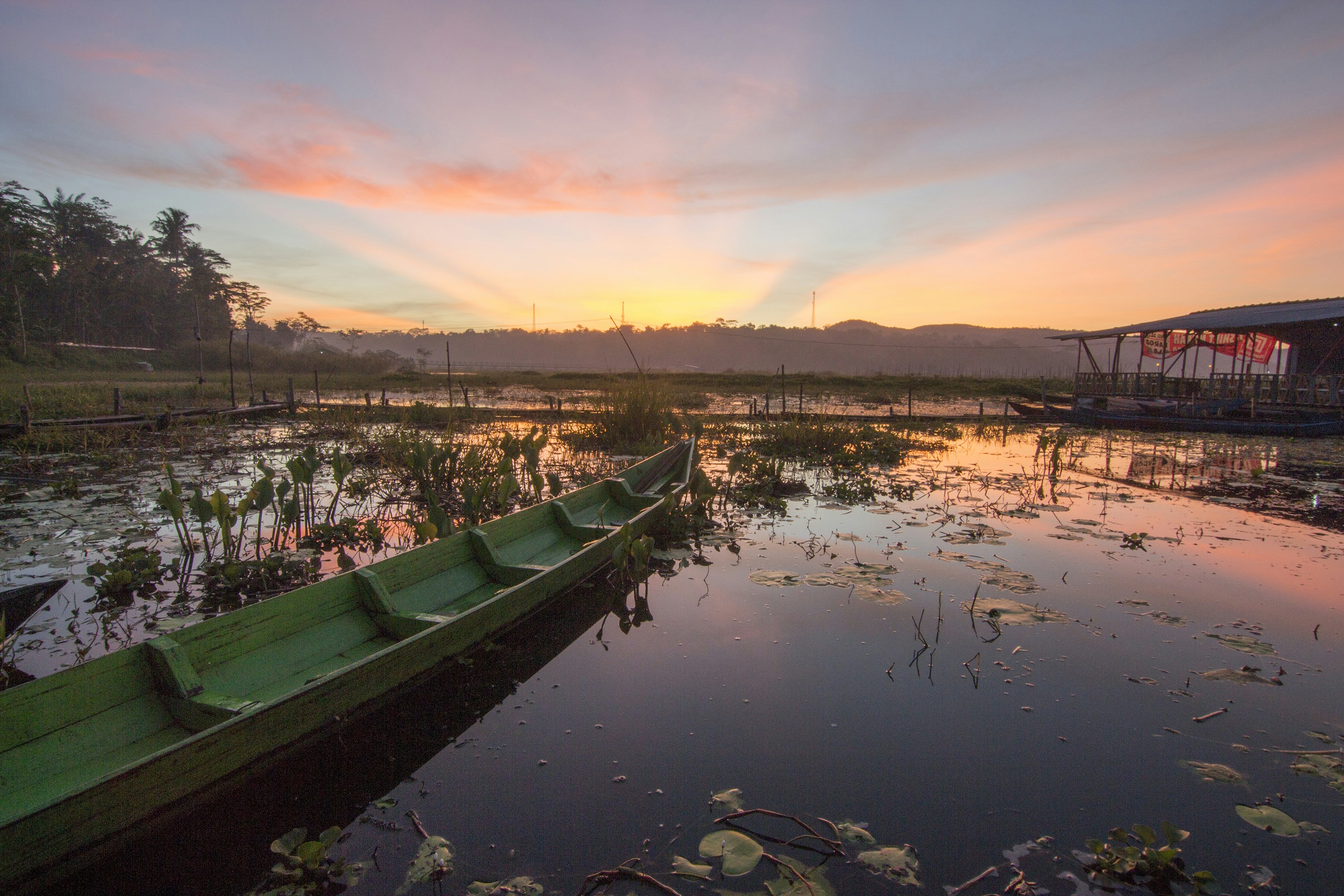 Sunrise Over a Green Boat on a Still Lagoon