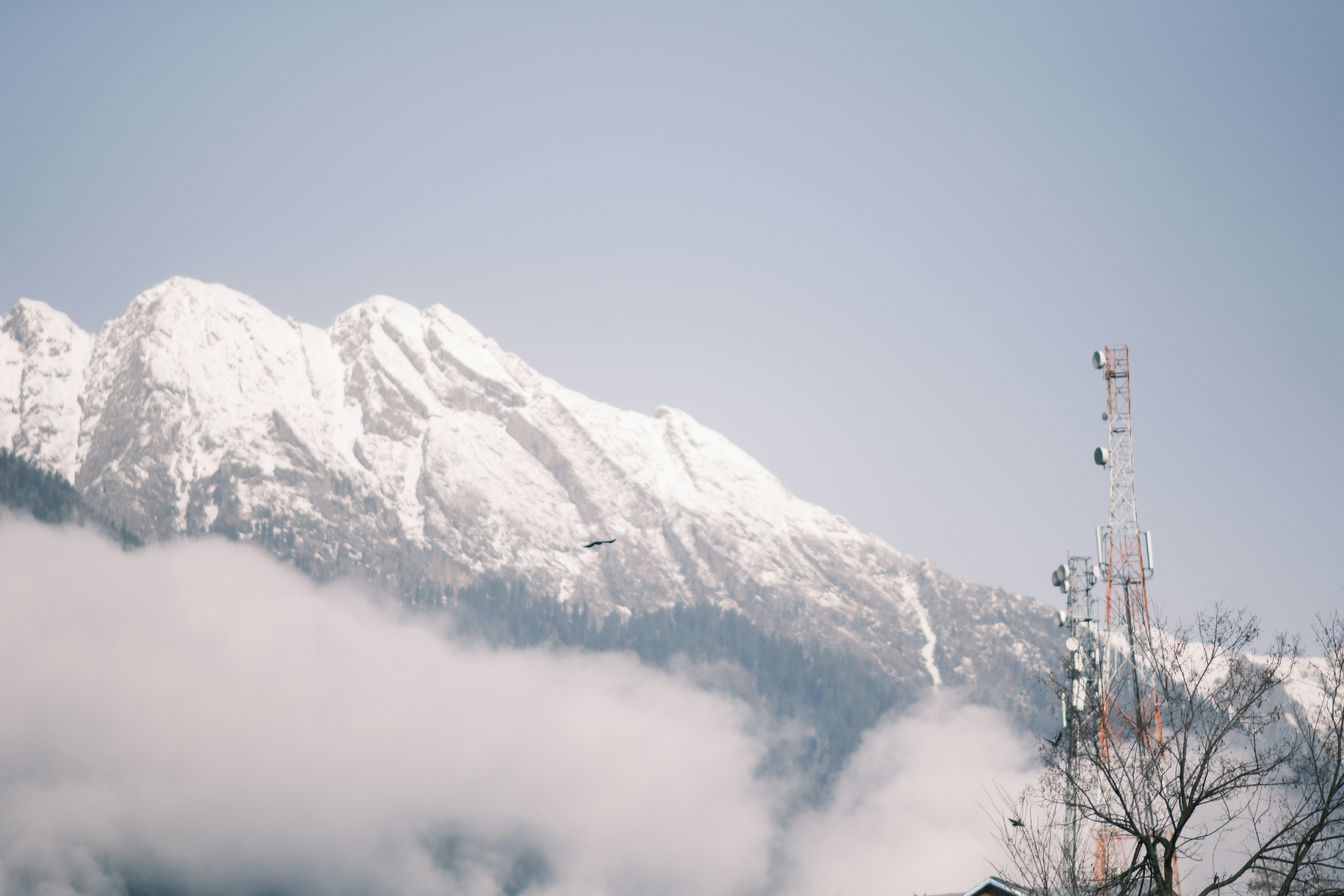 Snow-Capped Peaks Framed by Cloud Roll and a Radio Tower