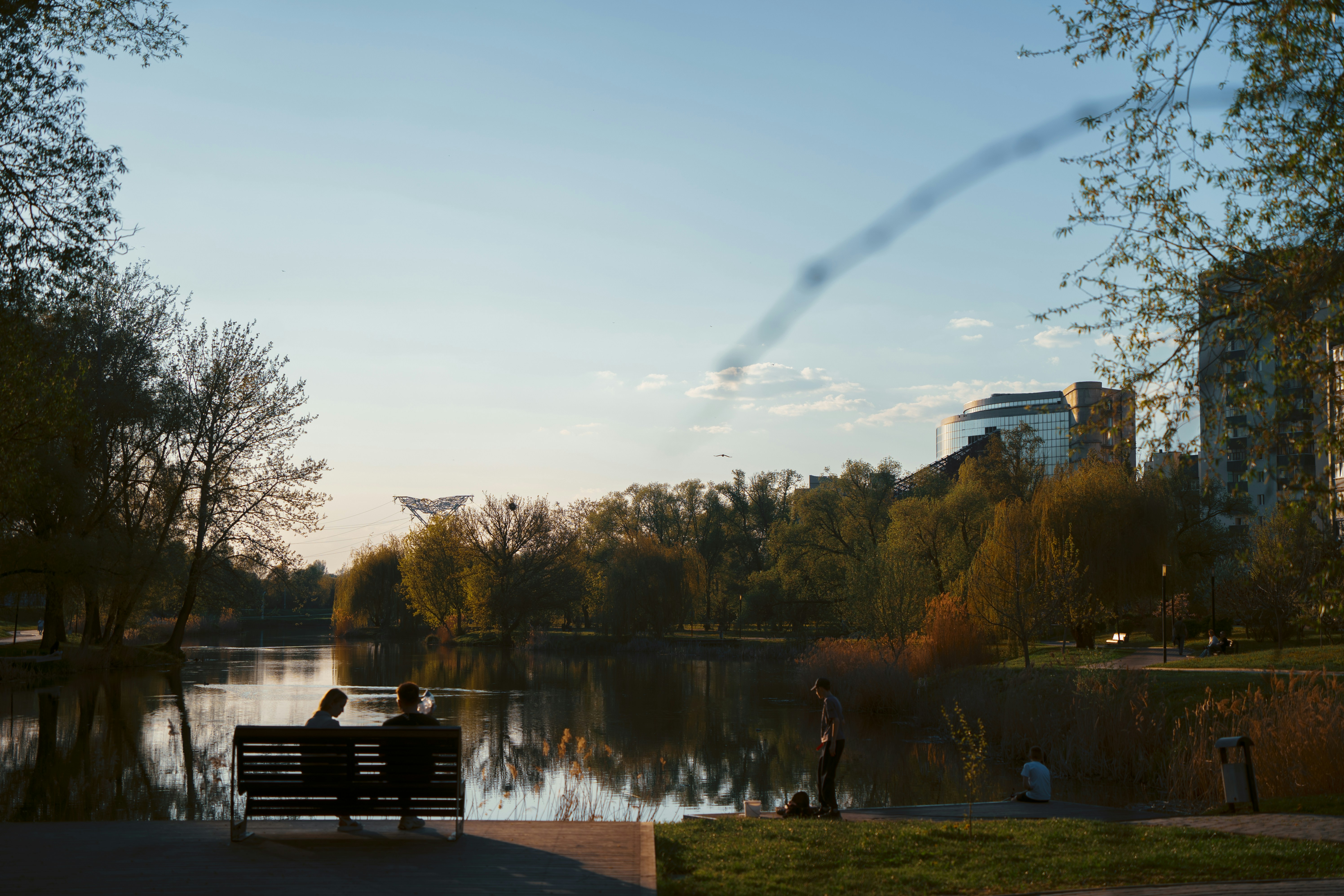 Serene City Lake at Dusk: Silhouettes on a Quiet Bench