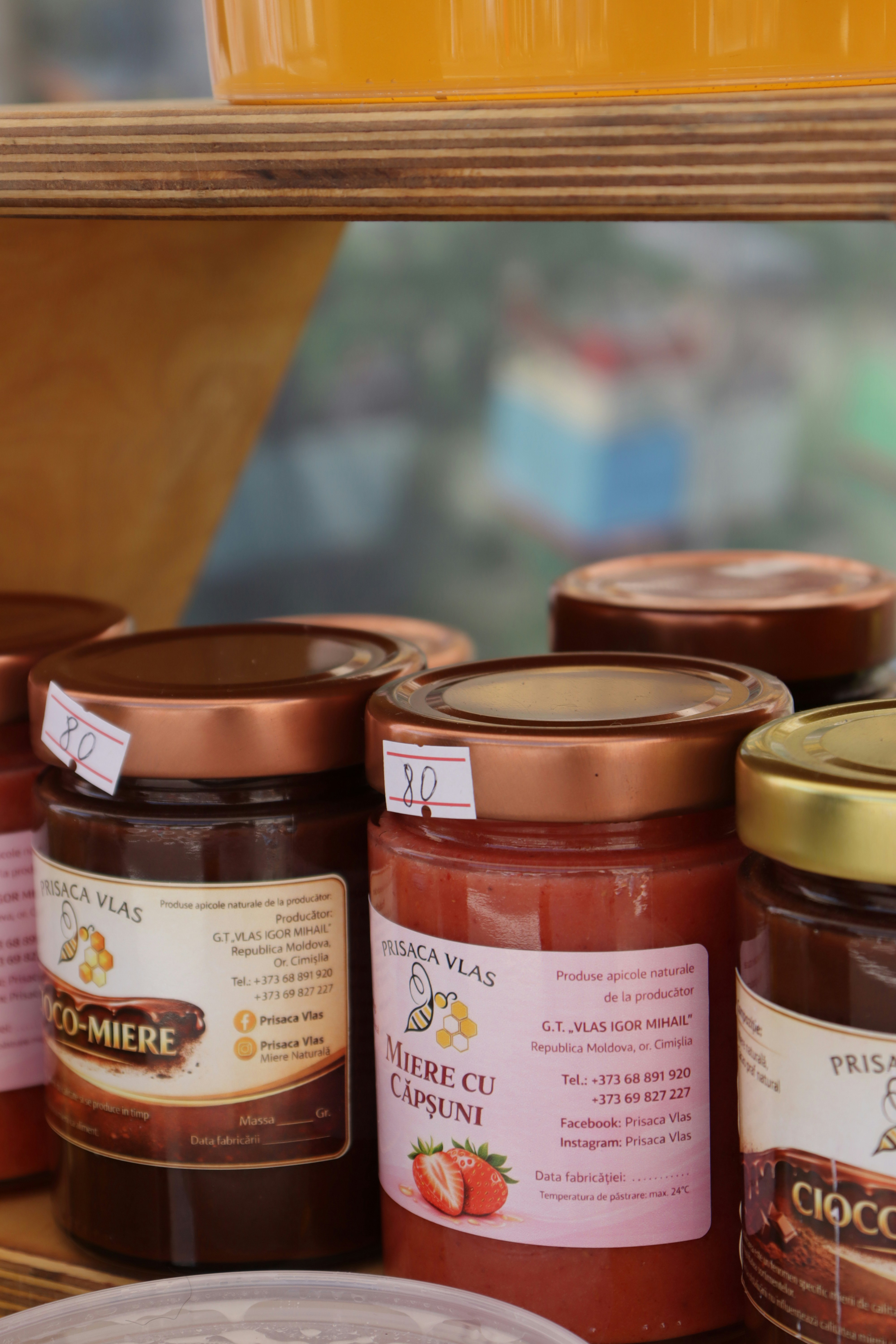 Glass jars of honey with labels on a wooden shelf