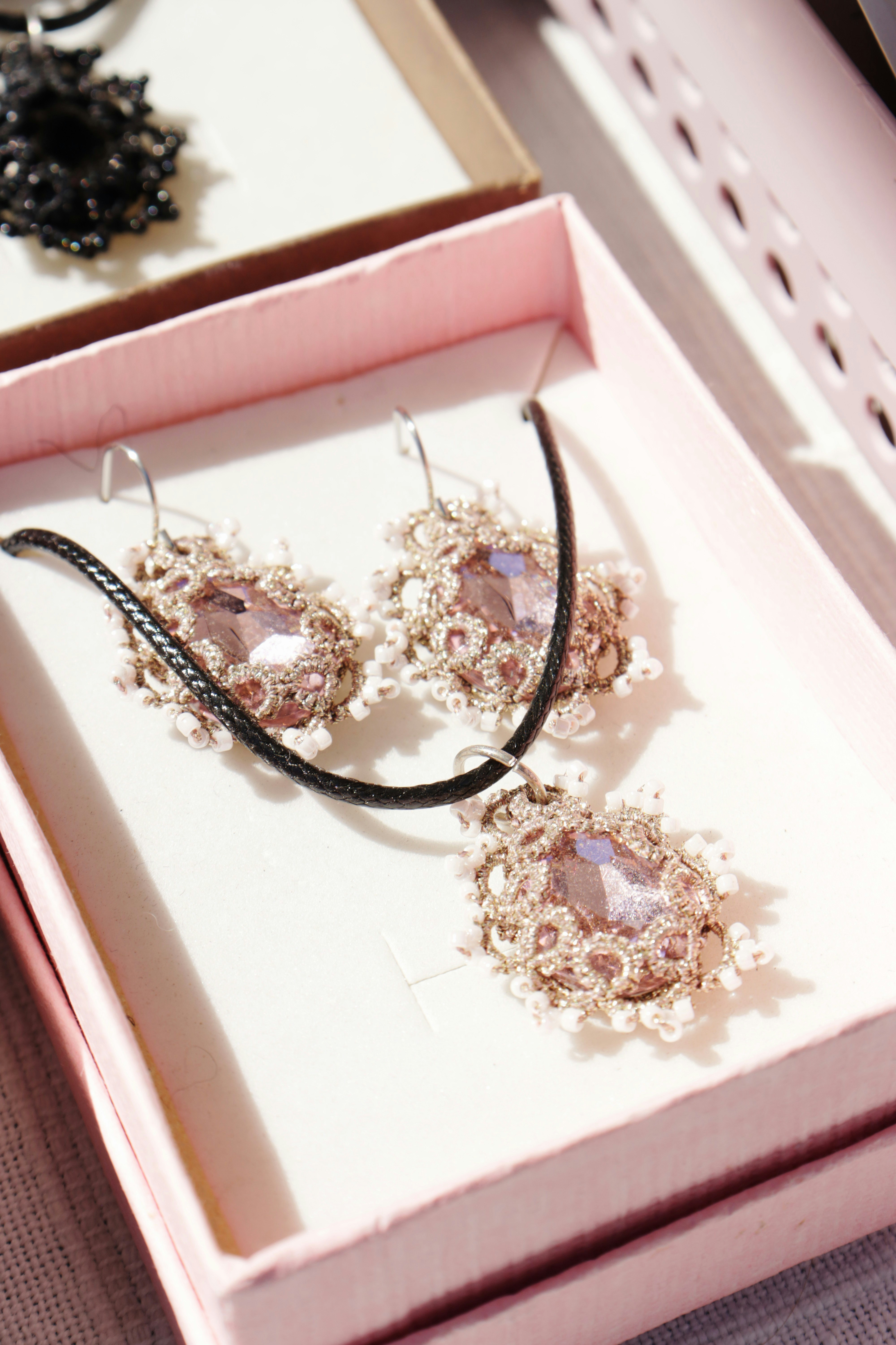 Pearled Charm: Delicate Jewelry Nestled in a Pink Cardboard Box