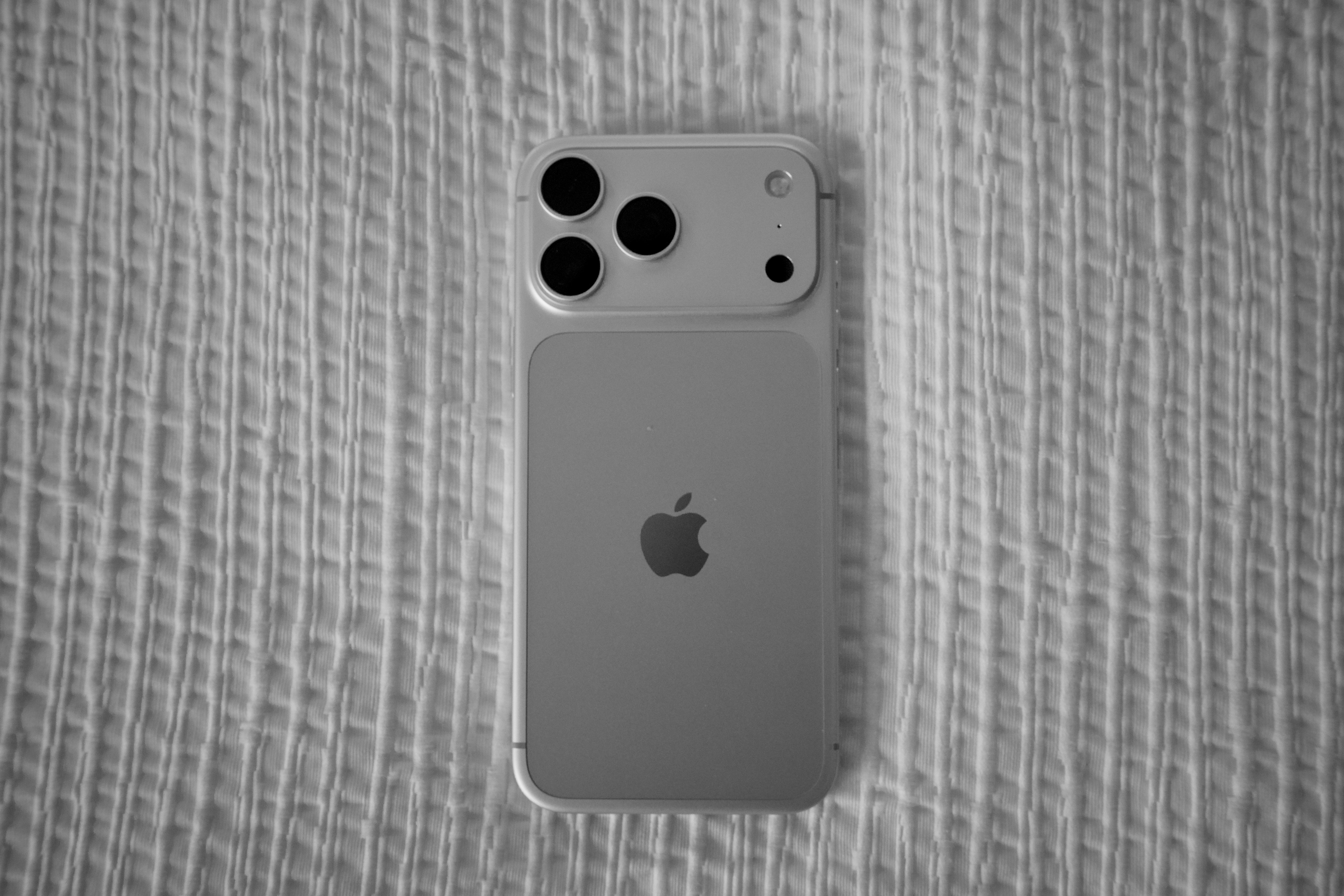 Central iPhone Back in Grayscale: A Minimalist Portrait of a Silver Phone on Textured Fabric