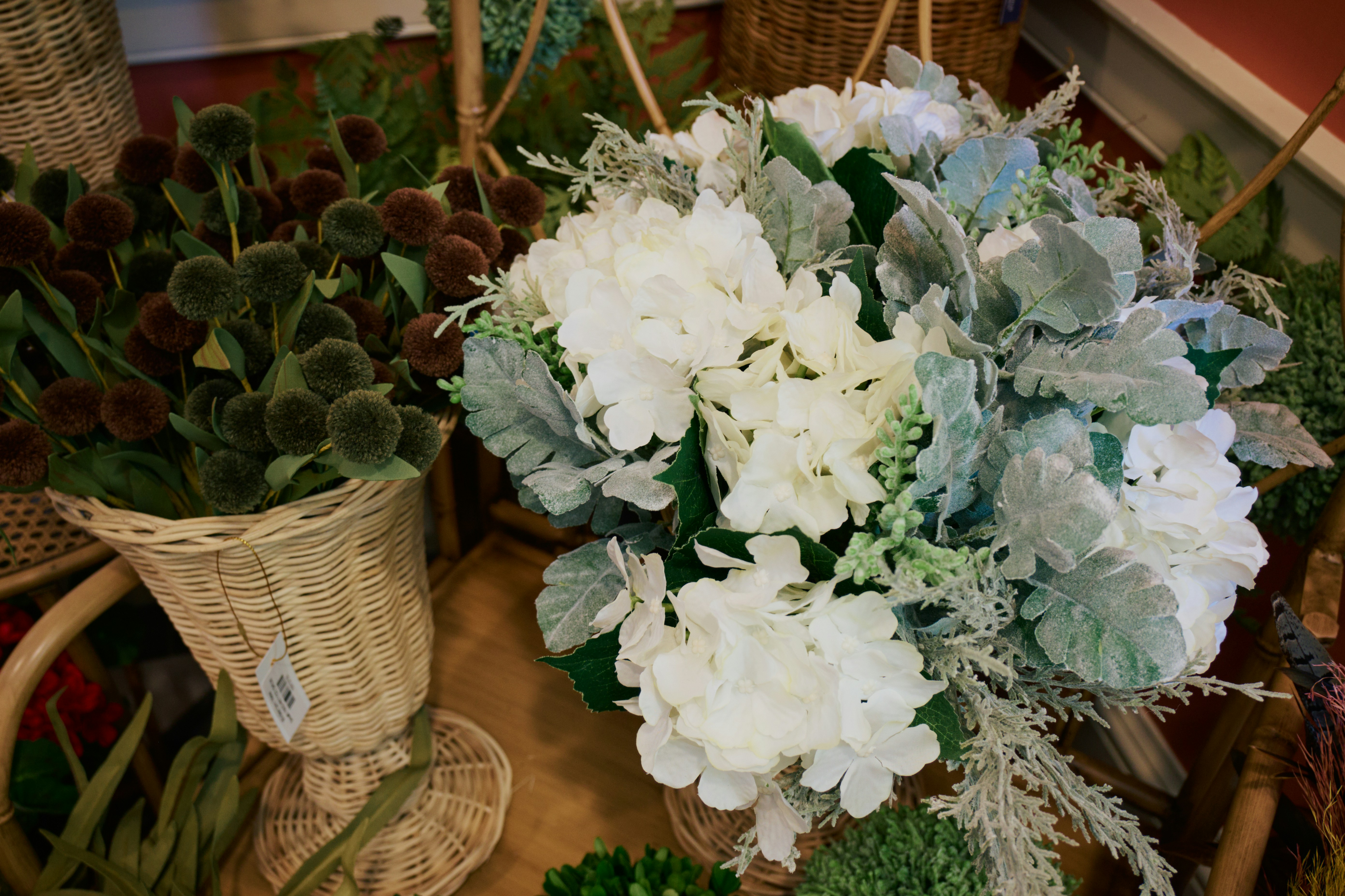 White hydrangea flowers and dusty miller leaves in a woven basket