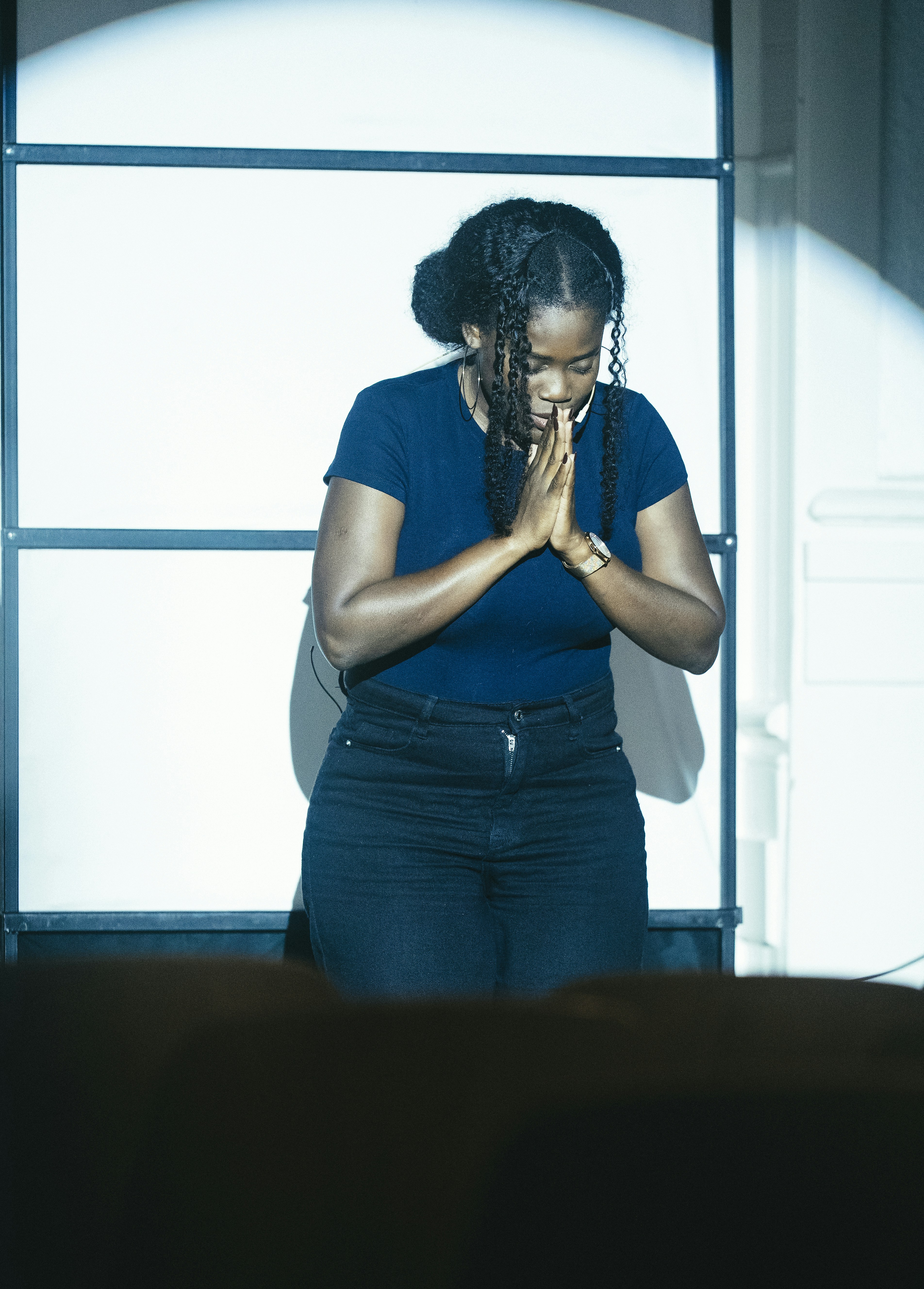 Prayerful Poise: A Quiet Moment in Front of the Windowed Backdrop