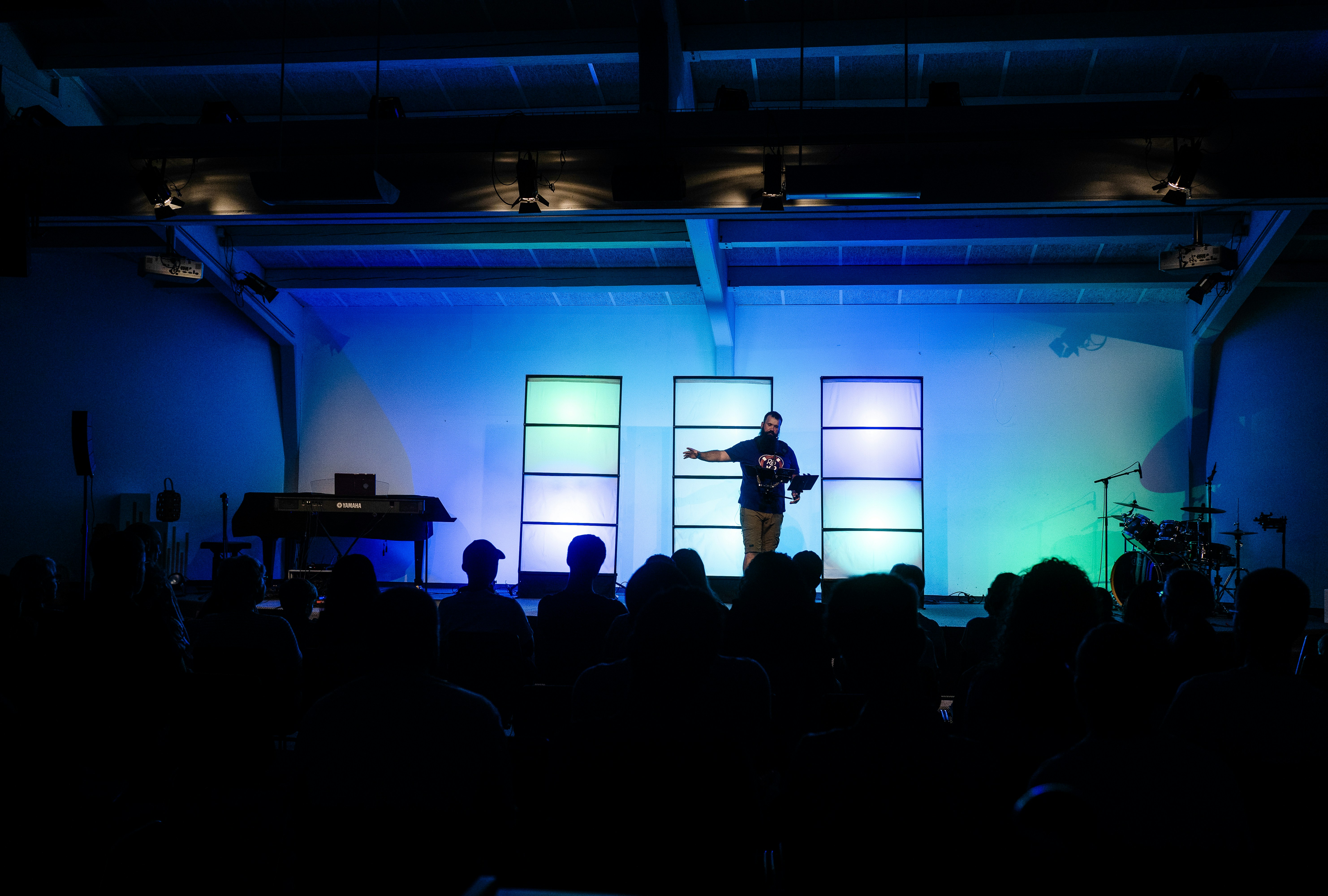 Center Stage under Neon Panels: A Performer Illuminates a Dim Auditorium