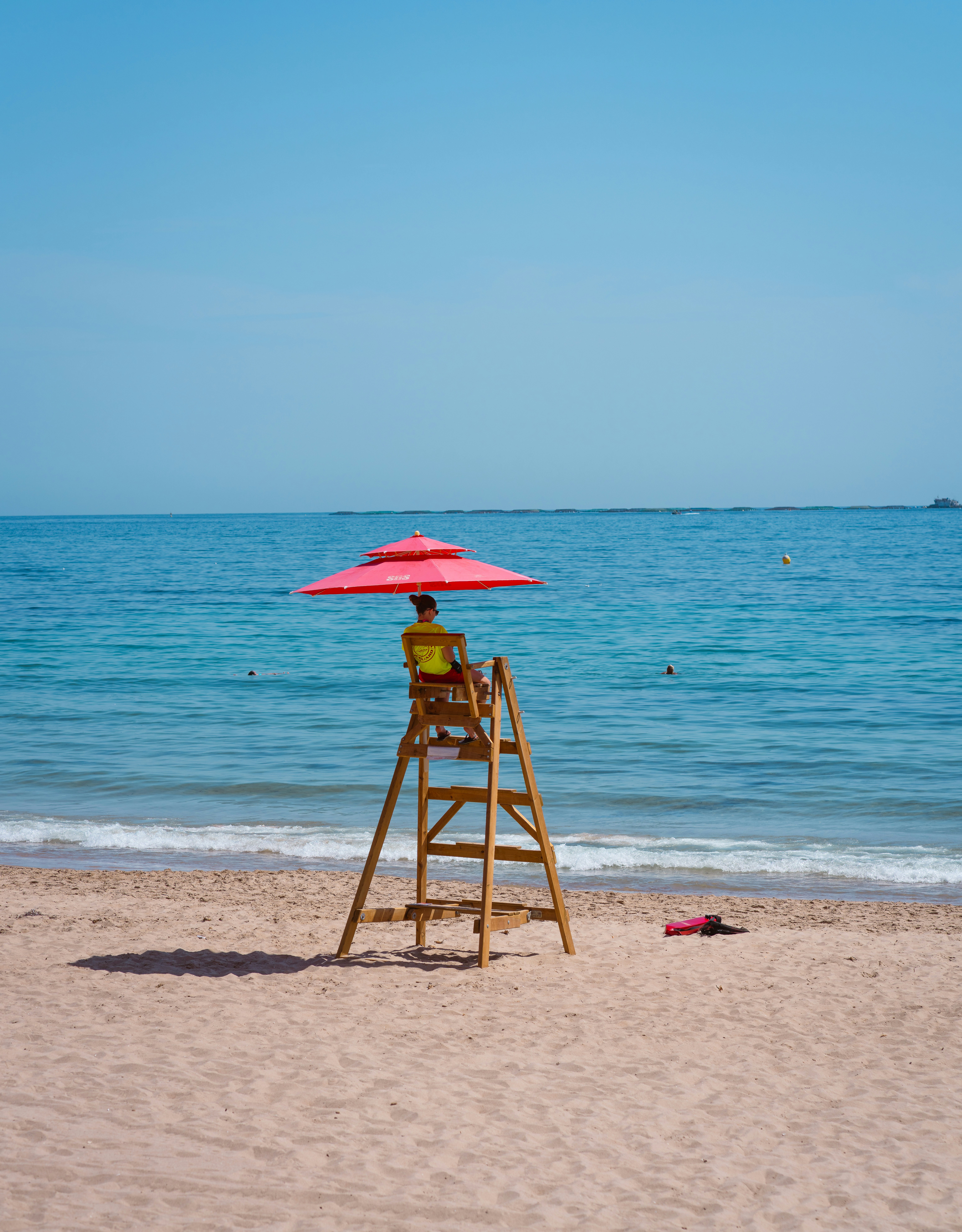 Lifeguard Stand under a Coral Umbrella on a Calm Beach