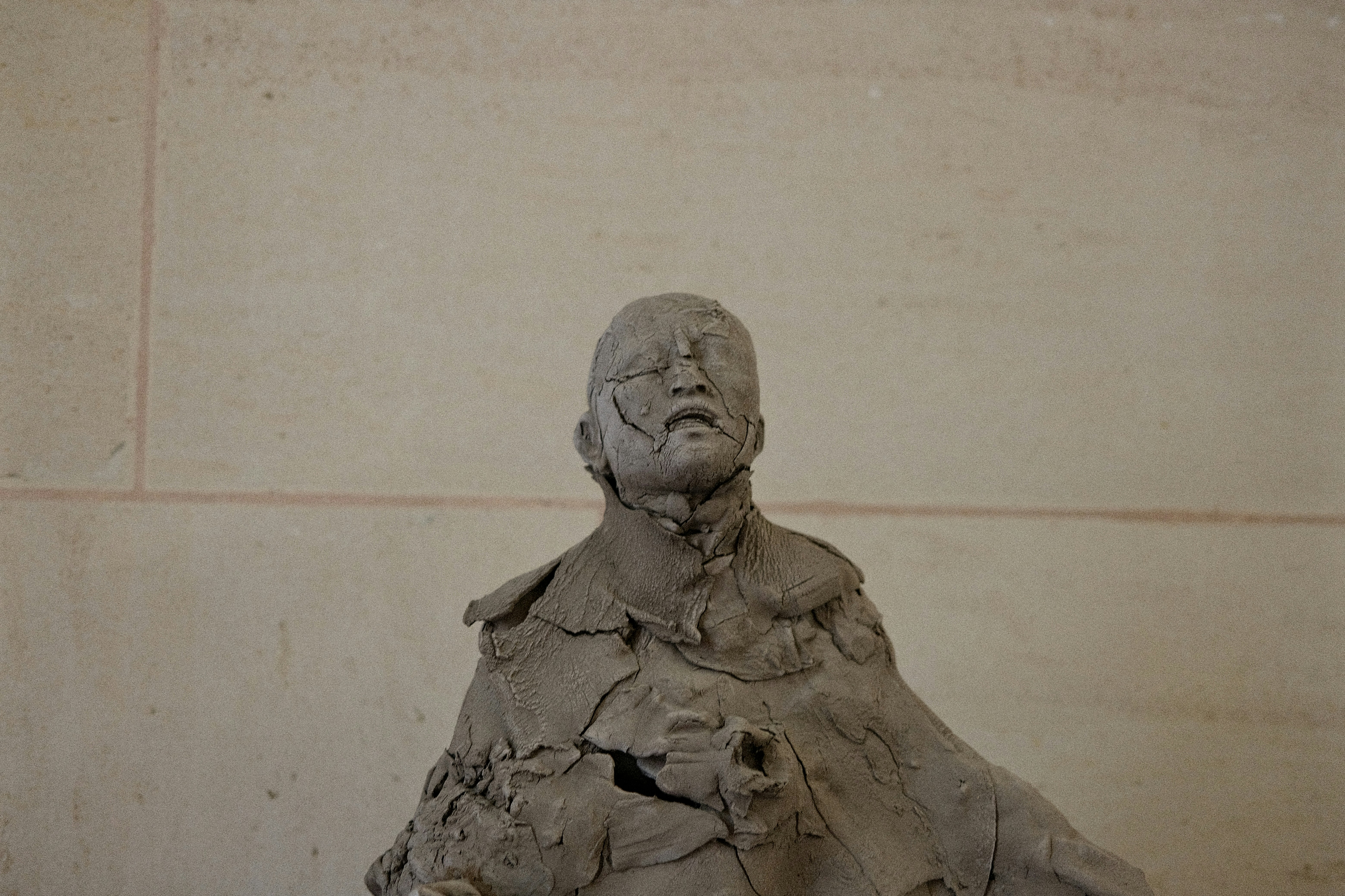 Clay Fragmented Figure on Aged Stone Wall
