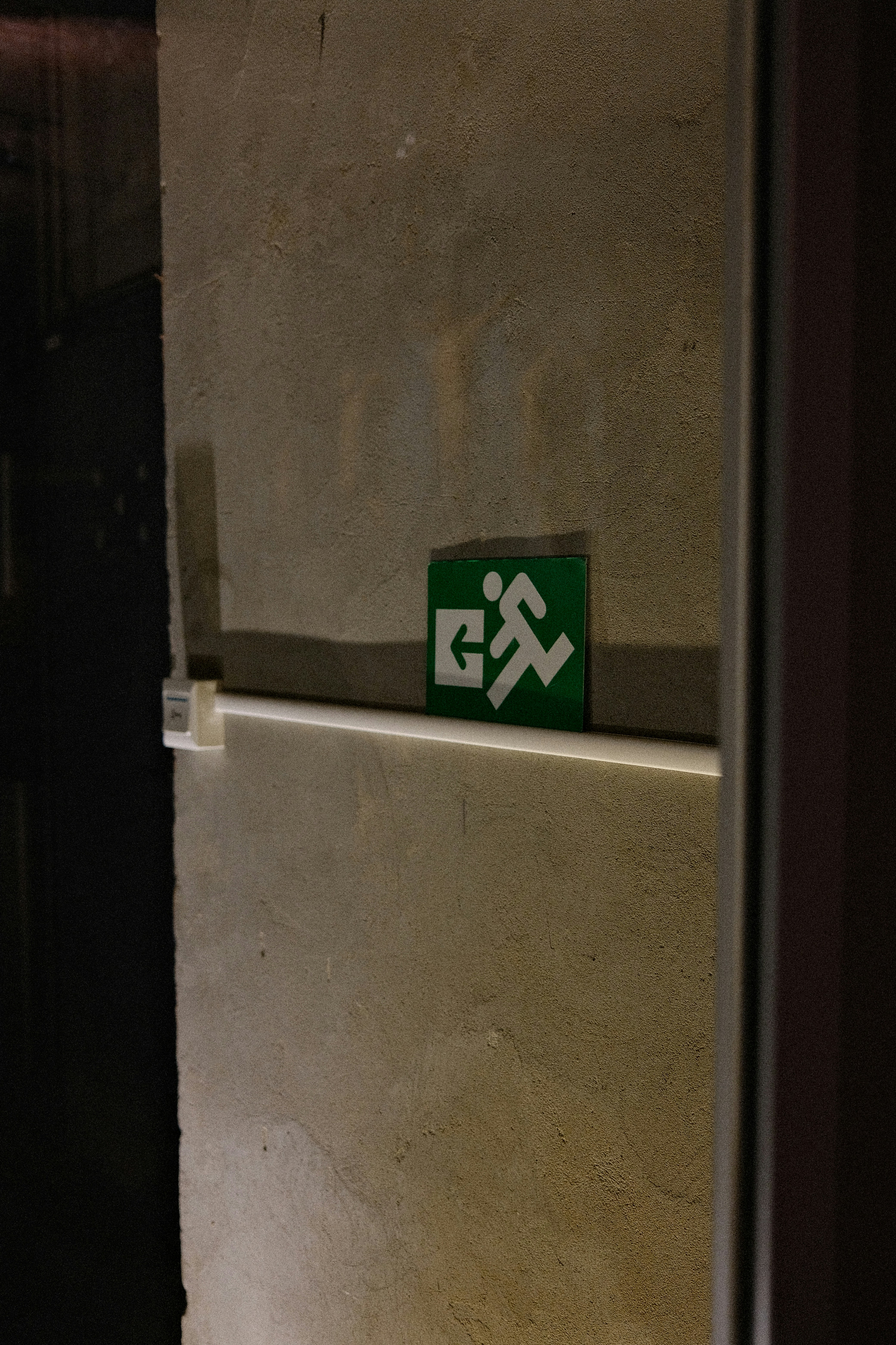 Emergency Exit Symbol in Dim Concrete Hallway