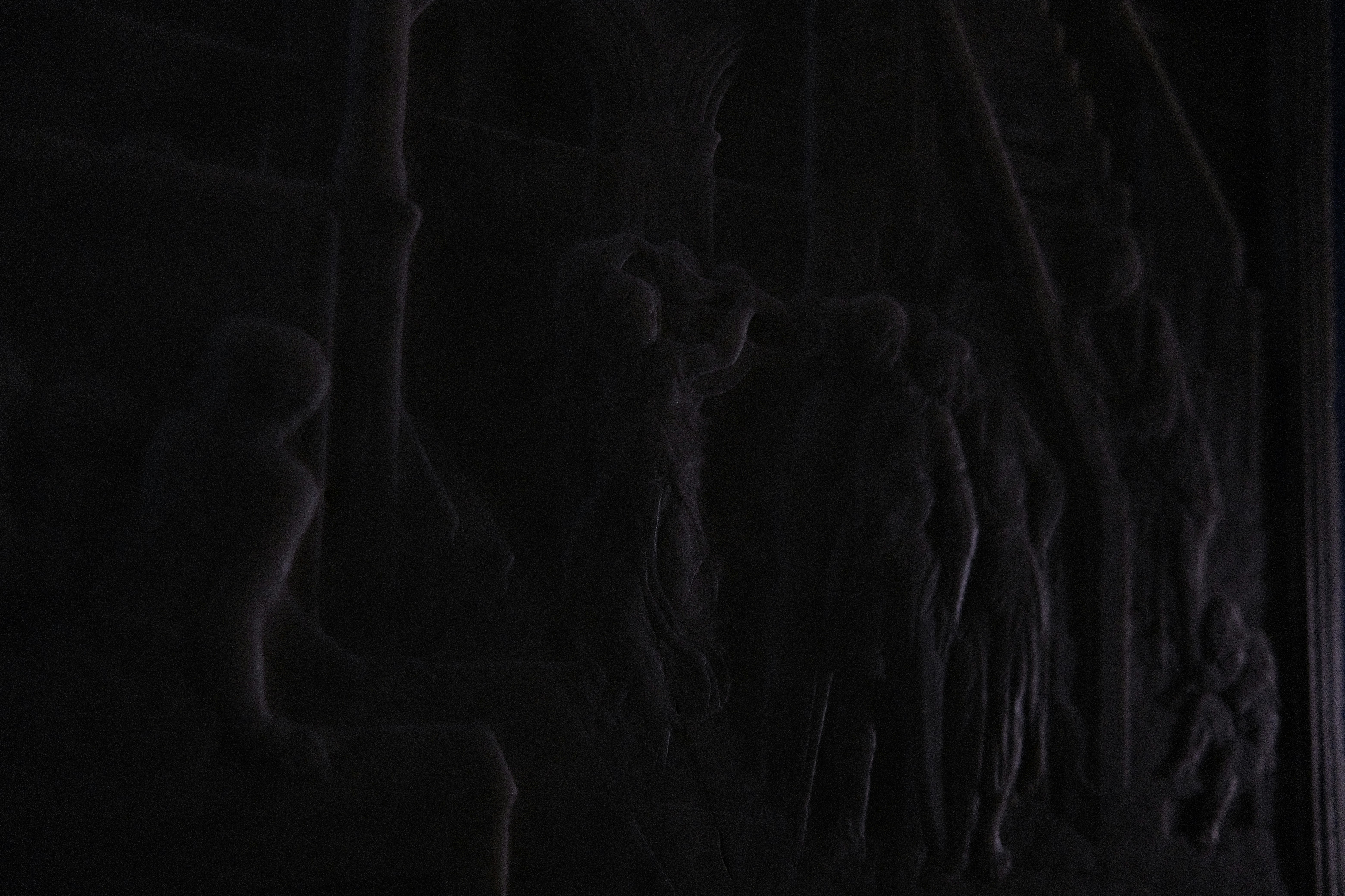 Silent Relief in Low Light: A Row of Figures in Shadowed Carved Corridor