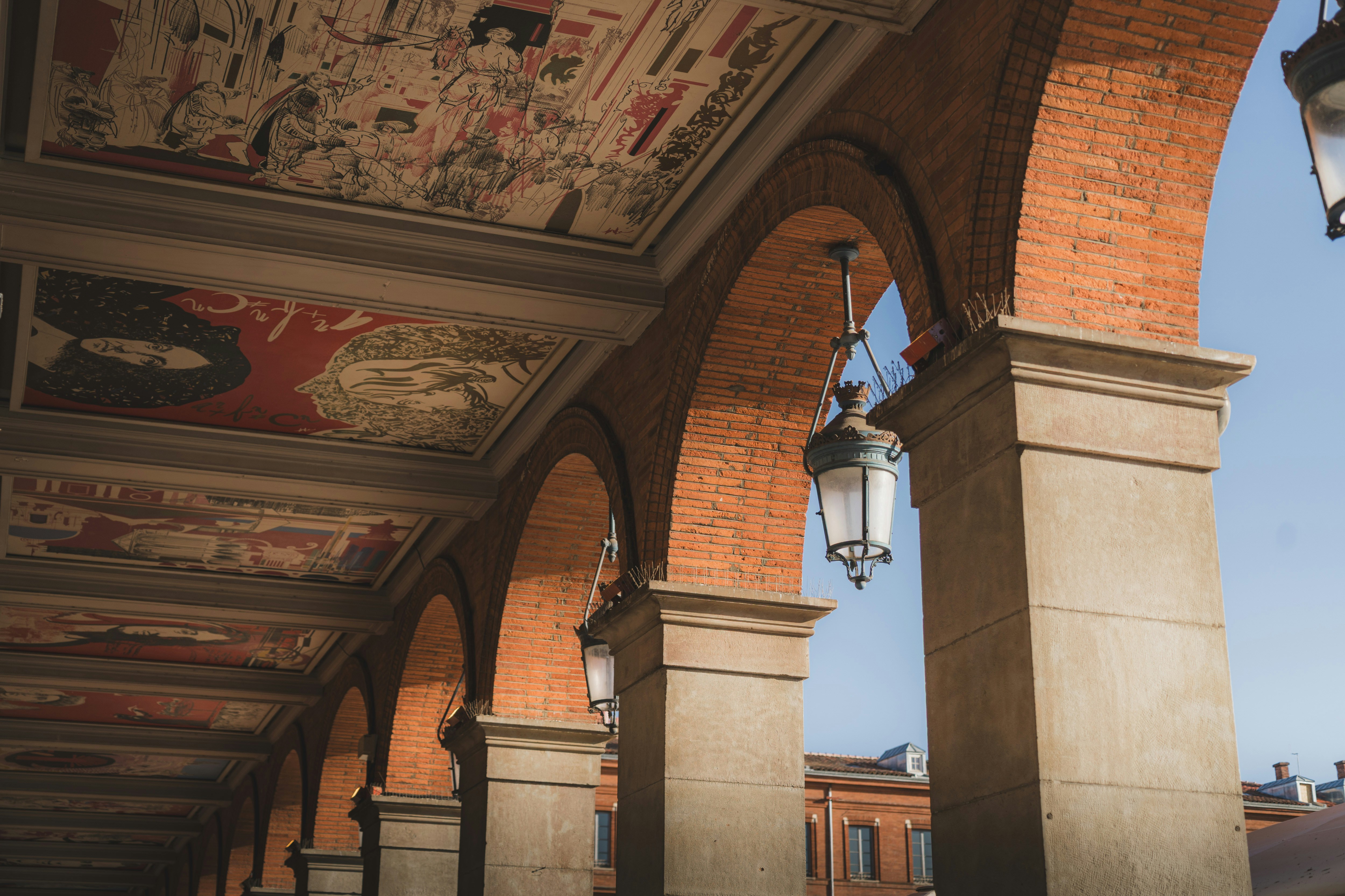 Arched Corridor over Brick and Stone: A Row of Lanterns under Painted Ceilings