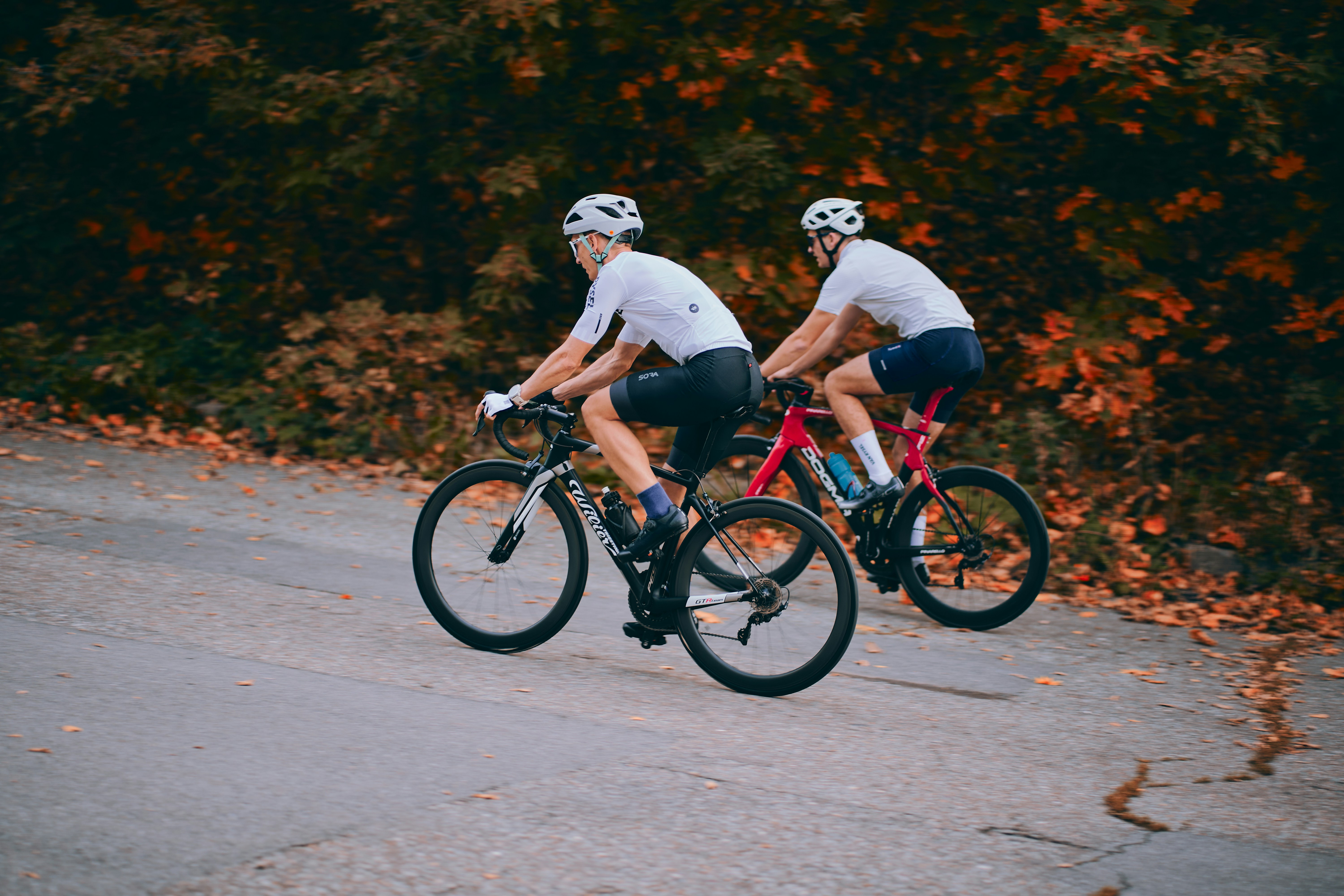 Racing in Tandem: Two Cyclists in White Helmets on Autumn Road