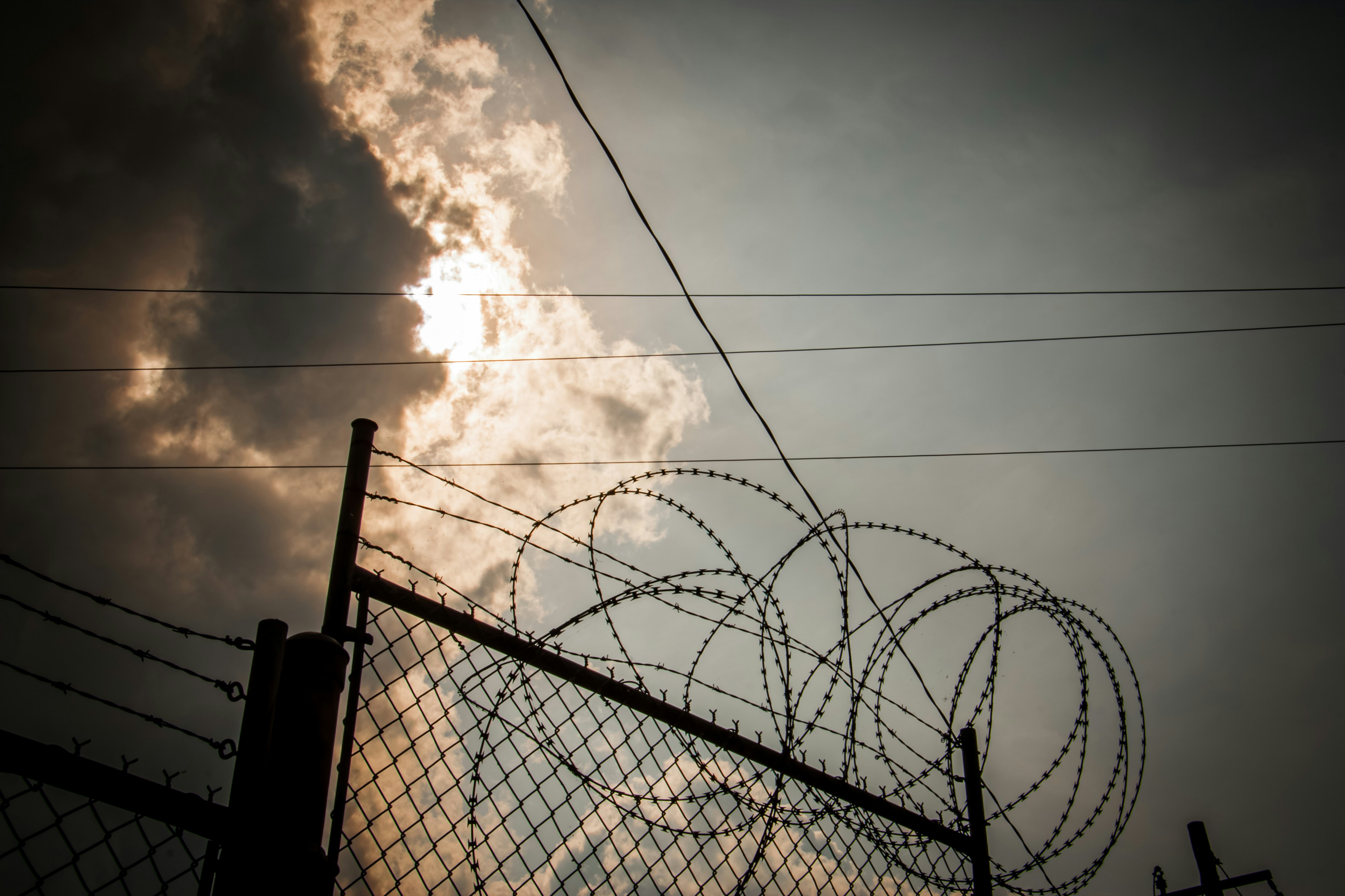 Barbed Horizon: Sunset Over a Security Fence