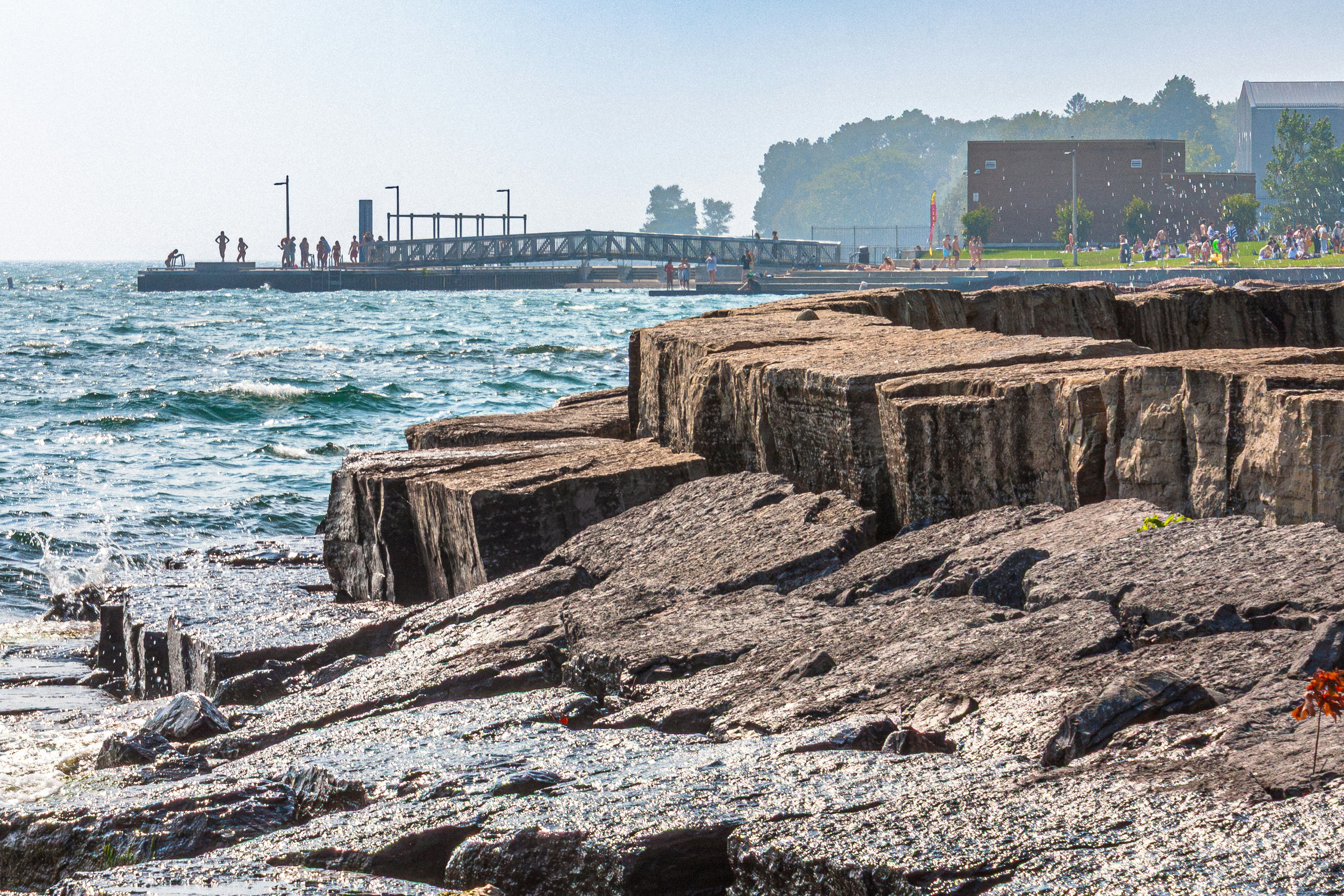 Rocky Breakwater Echoes: People and Pier at a Sunlit Seaside