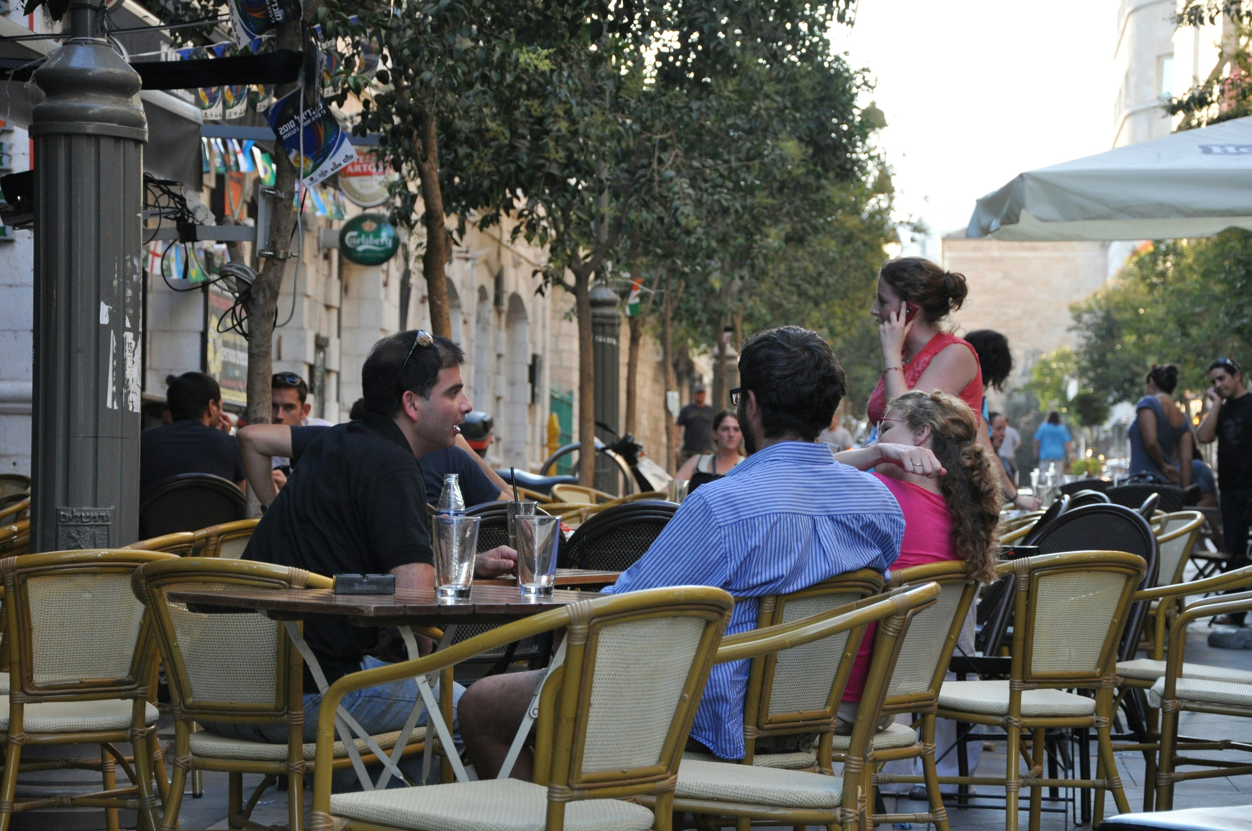 Conversation under the awning: sunlit courtyard cafe chatter