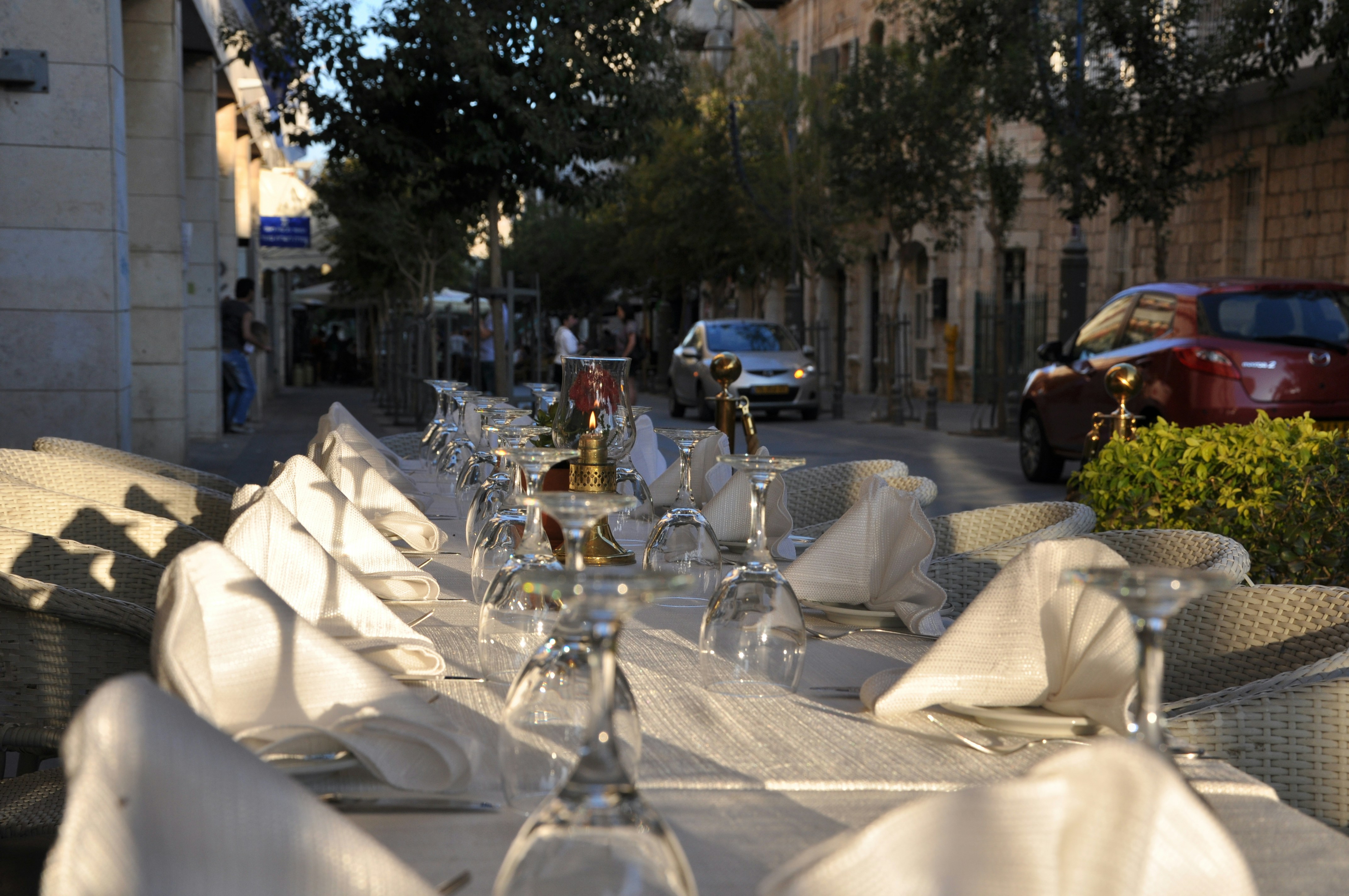 Sunlit Street-Side Table: Aline of Glassware on a Long Dining Setup