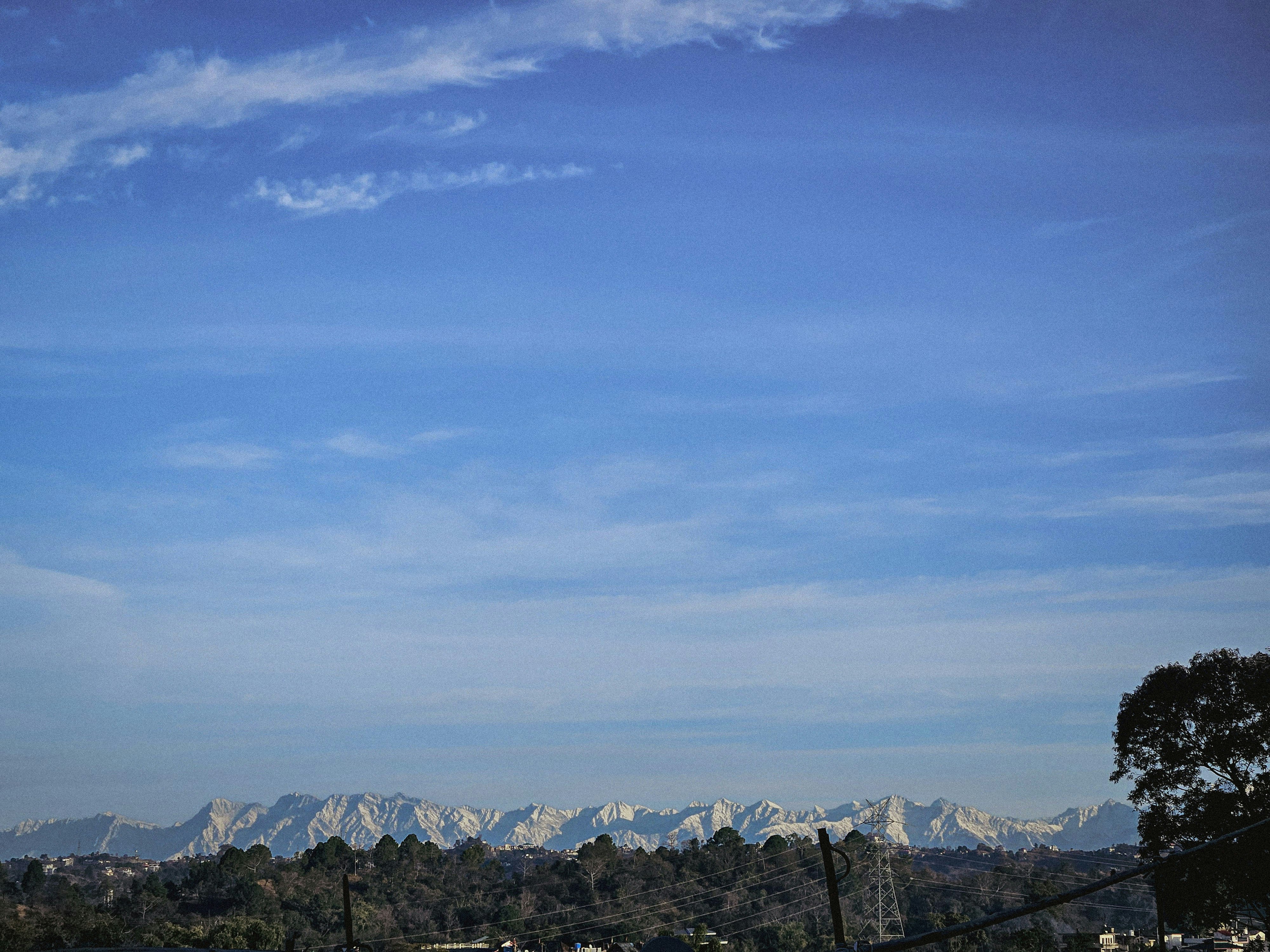 Snow-Capped Ridge at Distant Horizon Under Wide Blue Sky