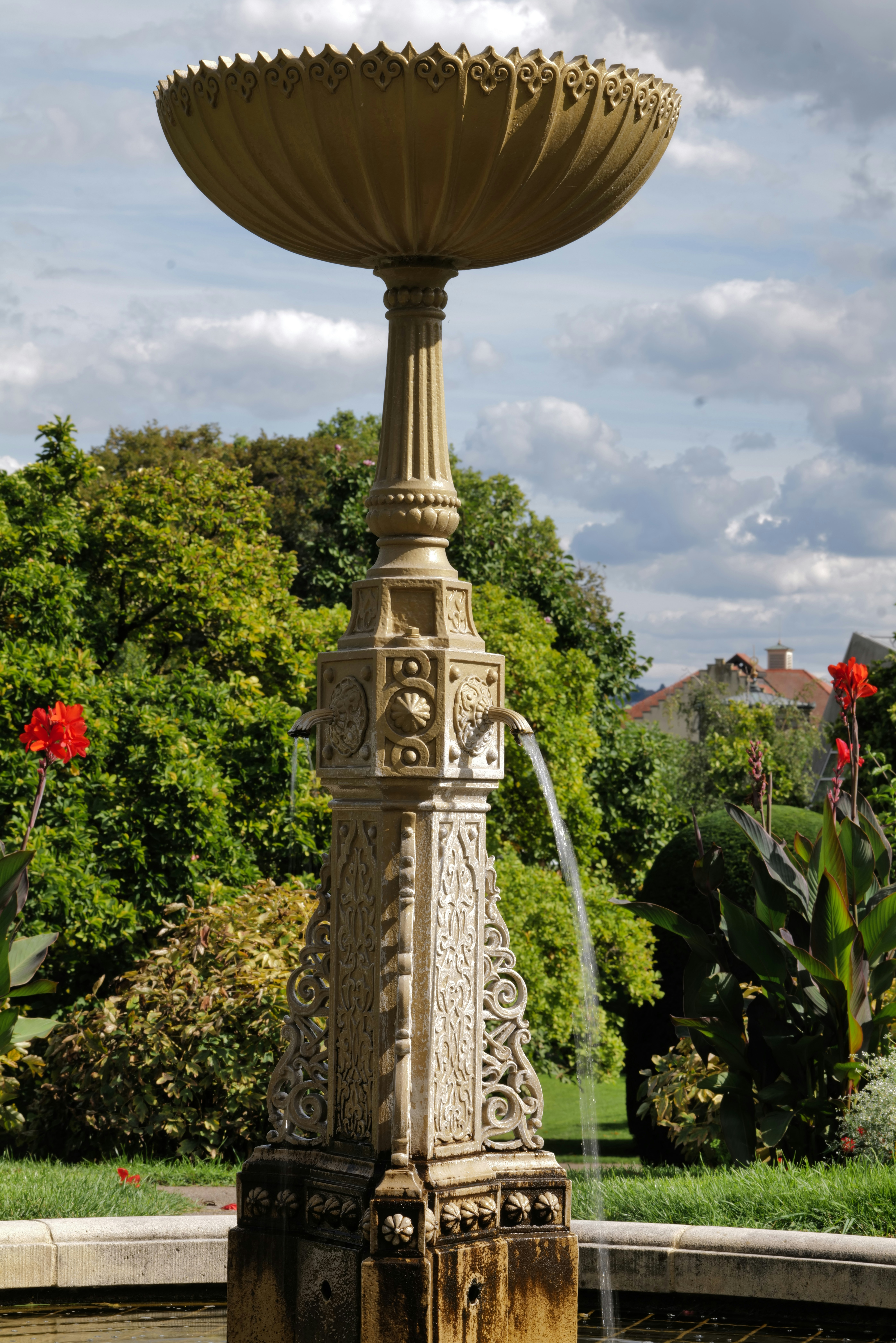 Granite Garden Fountain: A Sunlit Sentinel Amid Red Blooms