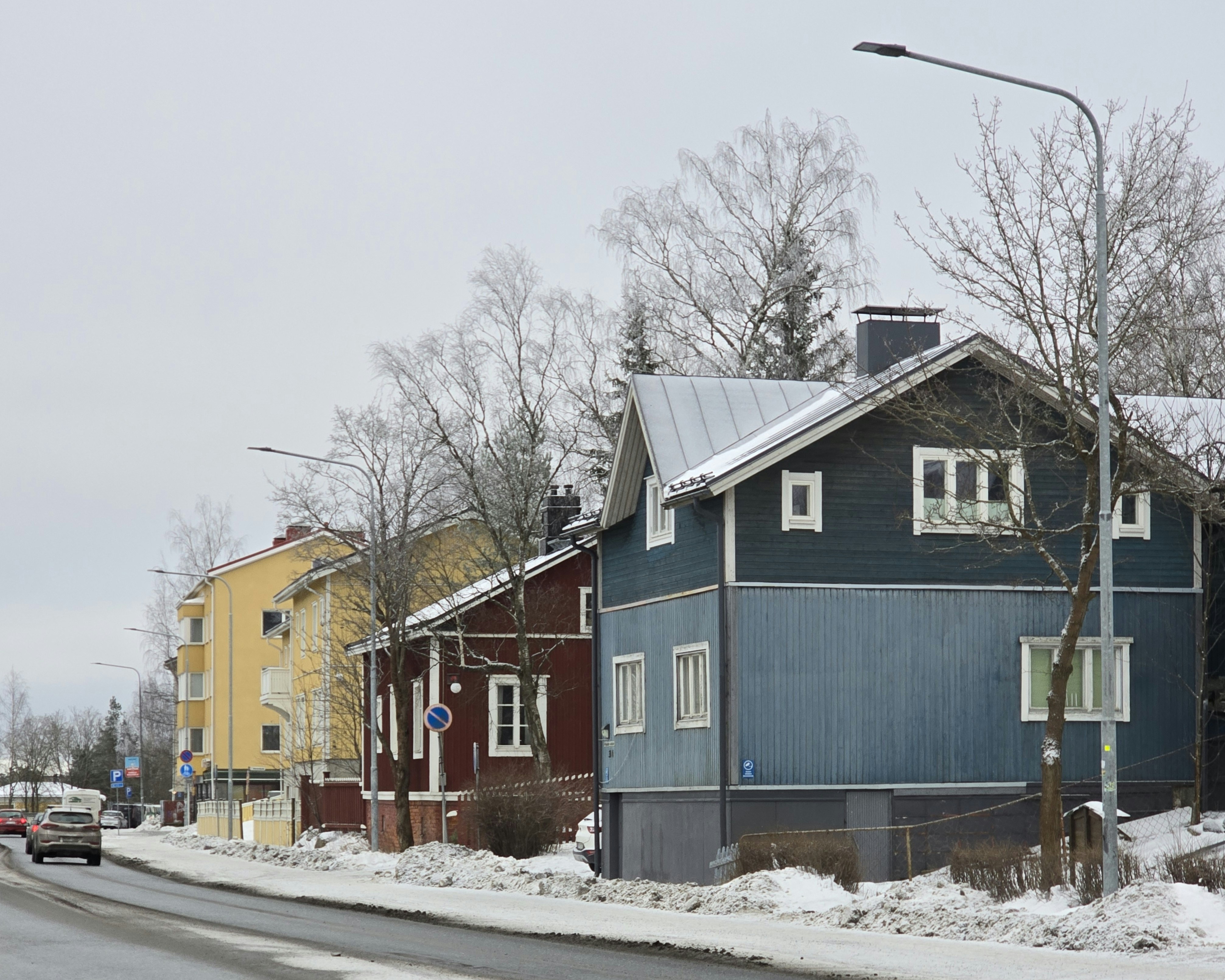 Blue house on a snowy street with colorful neighbors