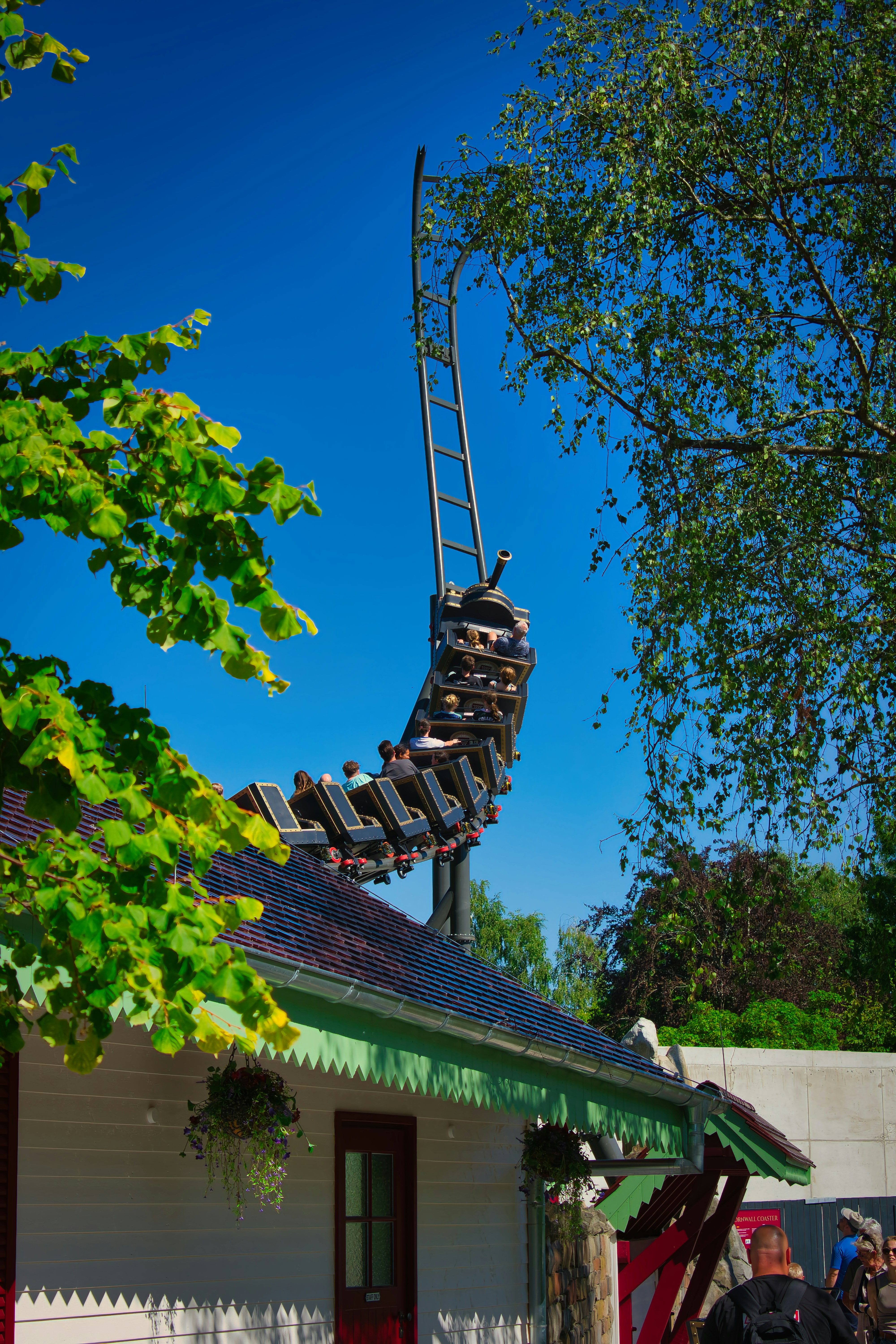  coil of a soaring ride: riders suspended in a steel serpent against a blue sky