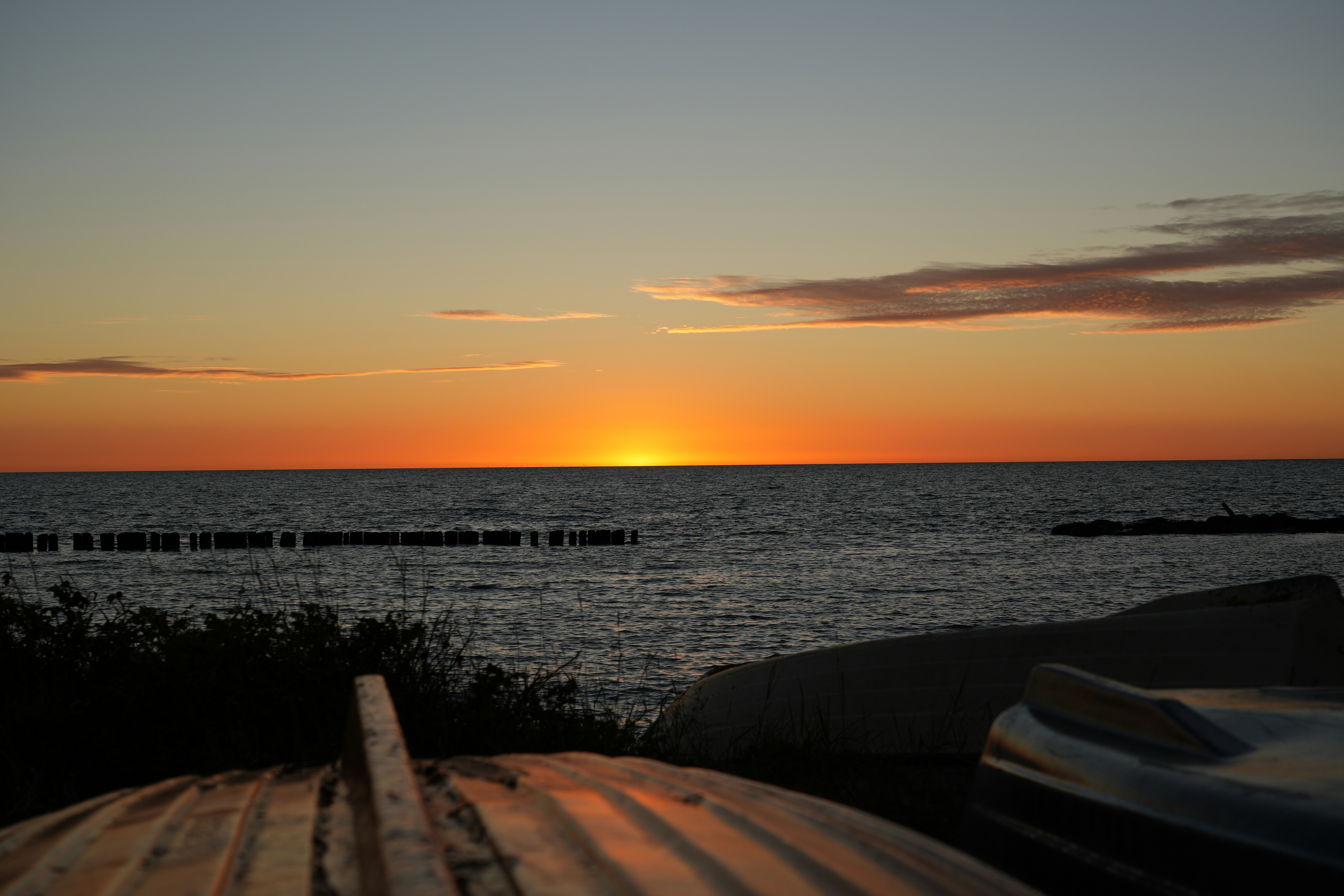 Sunlit Horizon: Boats Rest at Dusk Along a Quiet Shore
