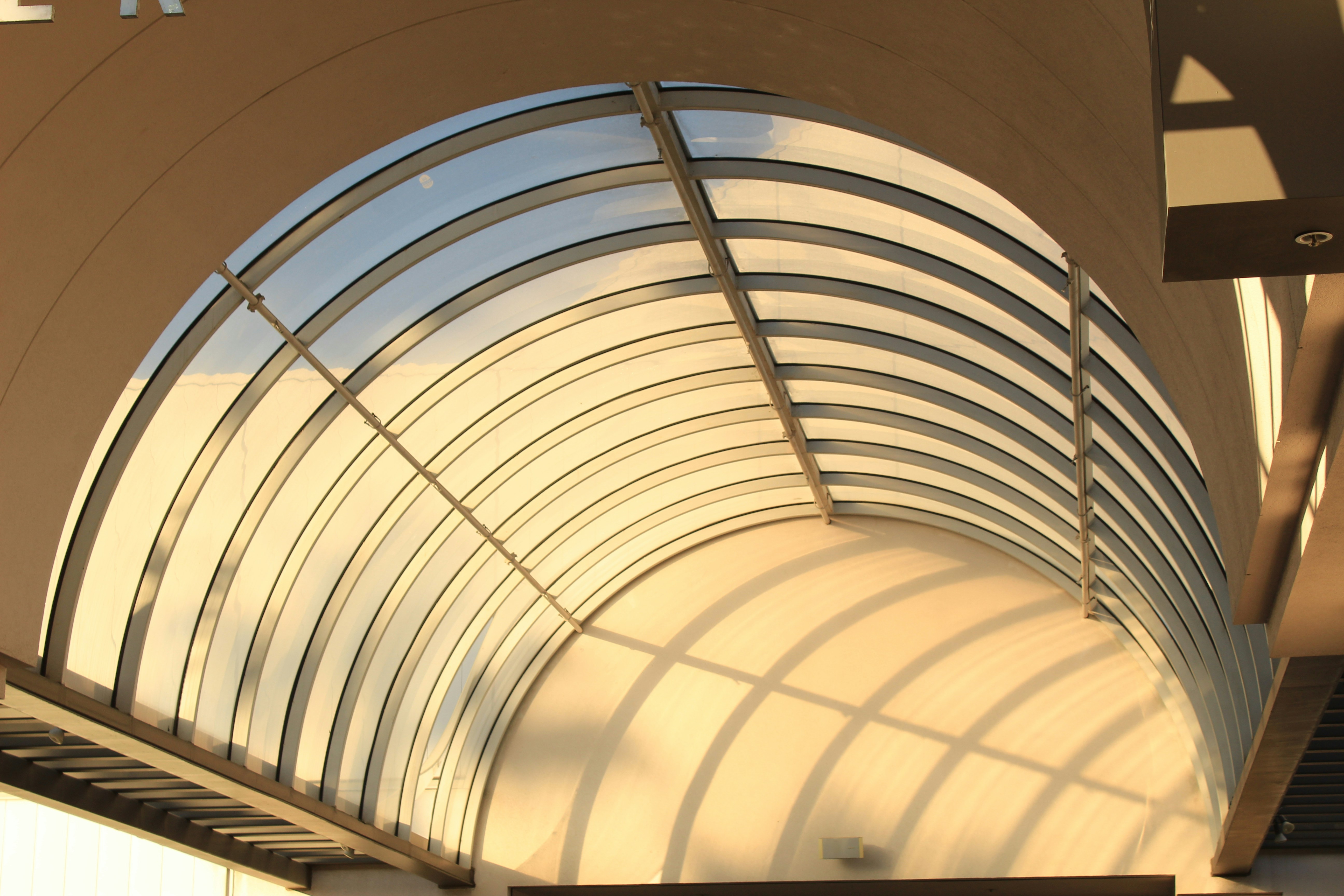 Curved Glass Corridor: Sunlit Arches and Cast Shadows