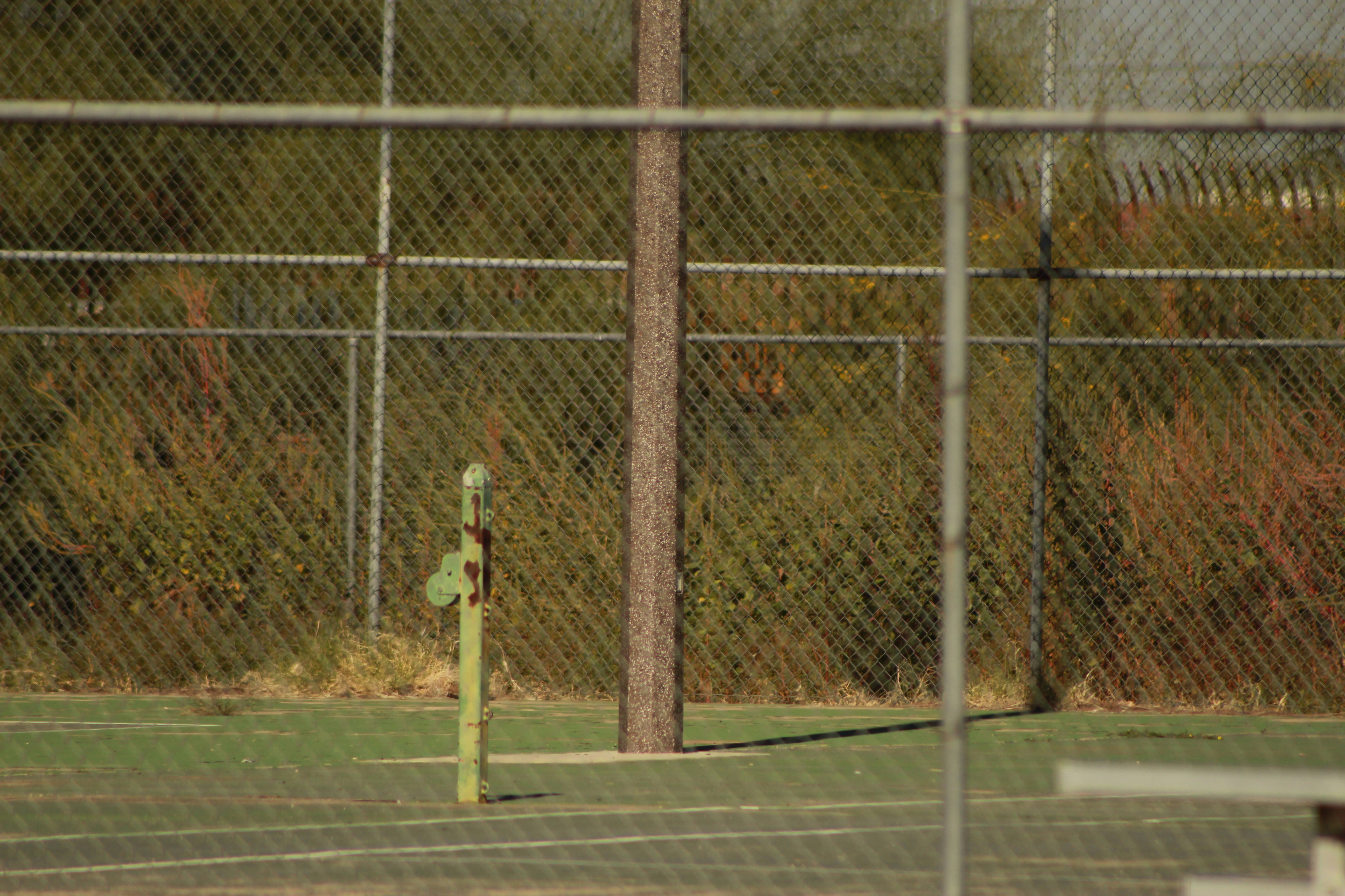Solitary Tennis Court Post Behind a Rusted Fence