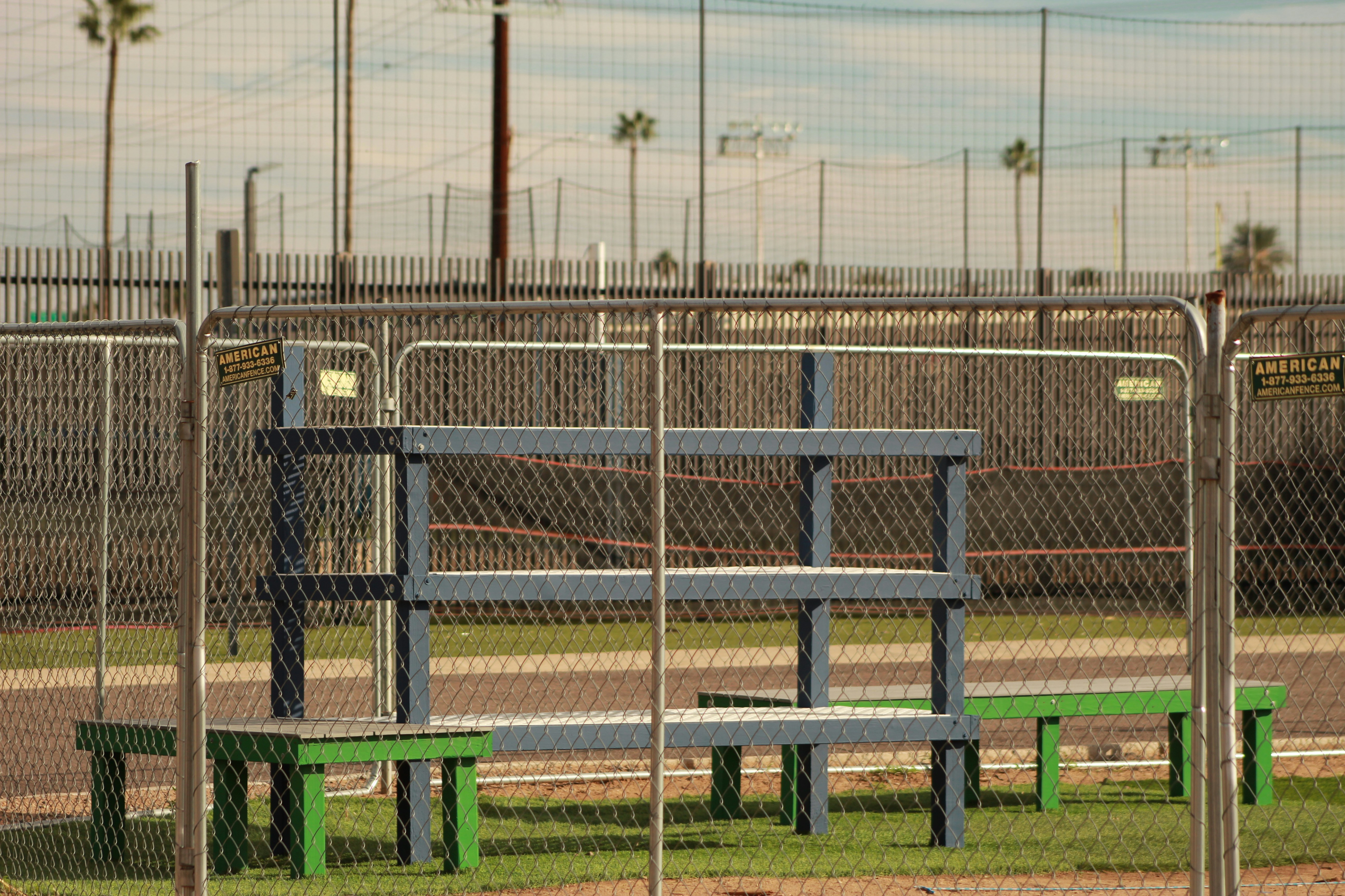 Bench Between Chain-Link Barriers: A Quiet Park View Through Fences