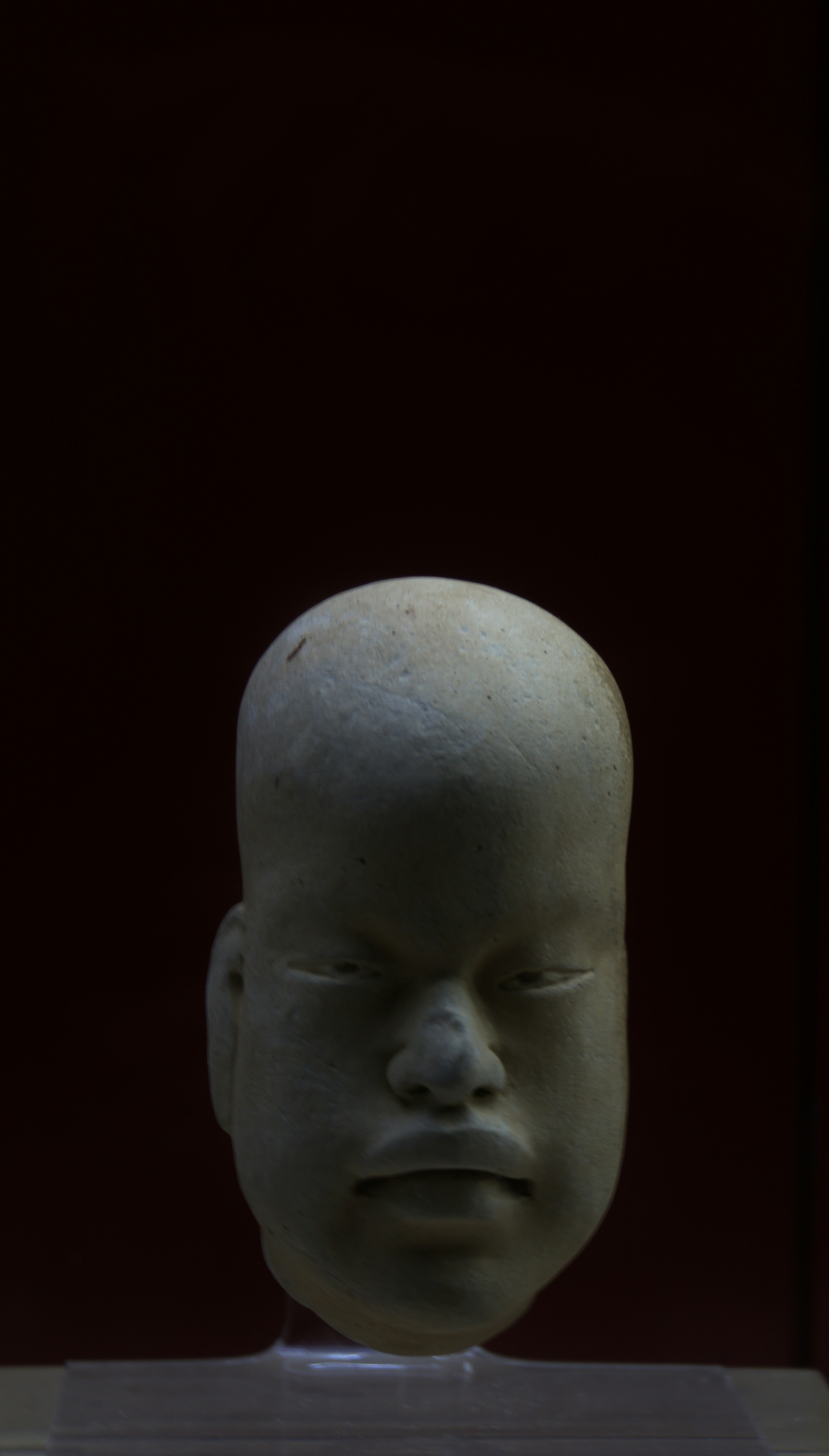 Ceramic Silence: a solitary stone bust under a velvet-dark backdrop