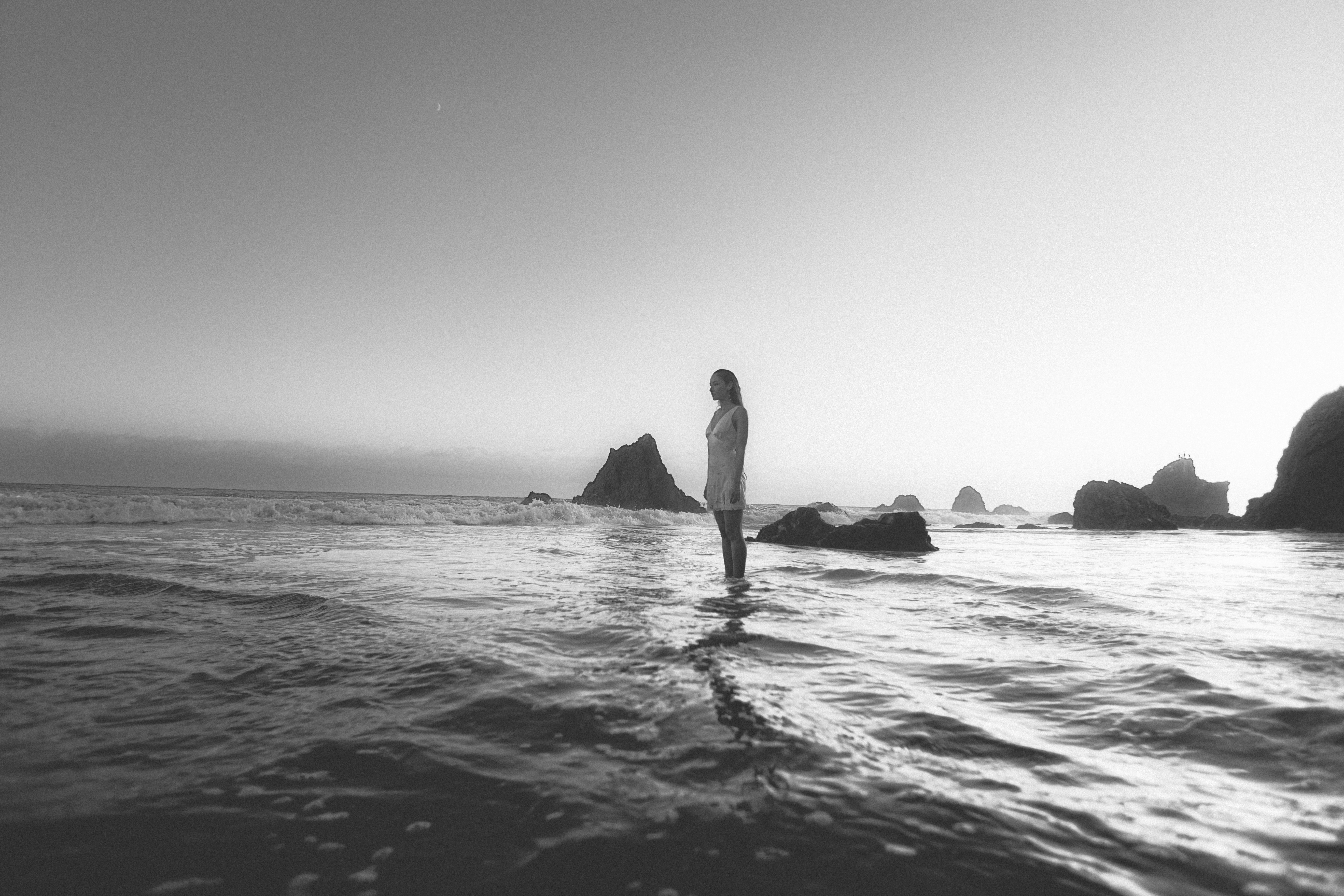  lone figure on a distant shore as waves carve a quiet line
