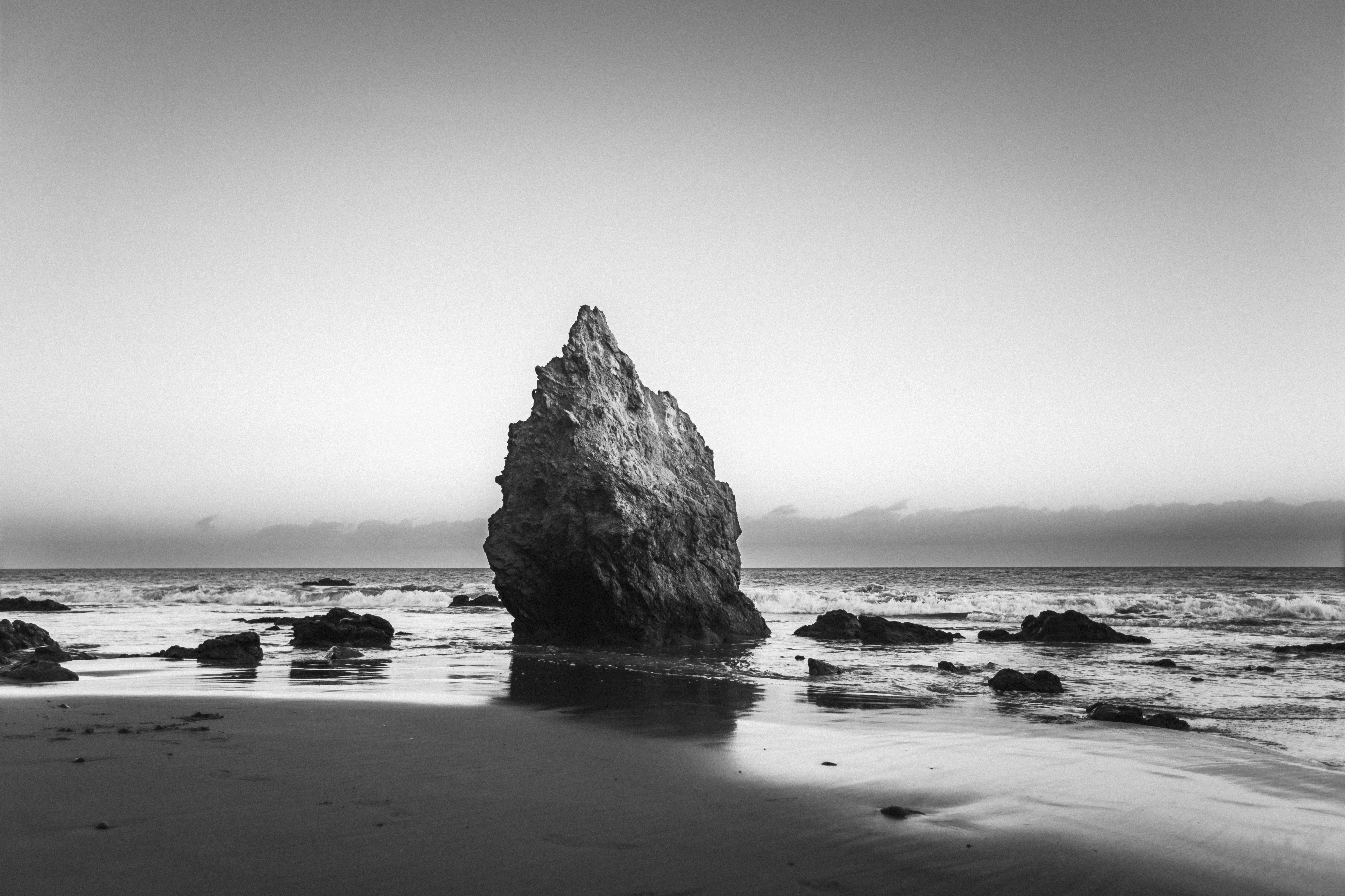 Sea-stone Sentinel: A lone rock rising from the shore at dusk