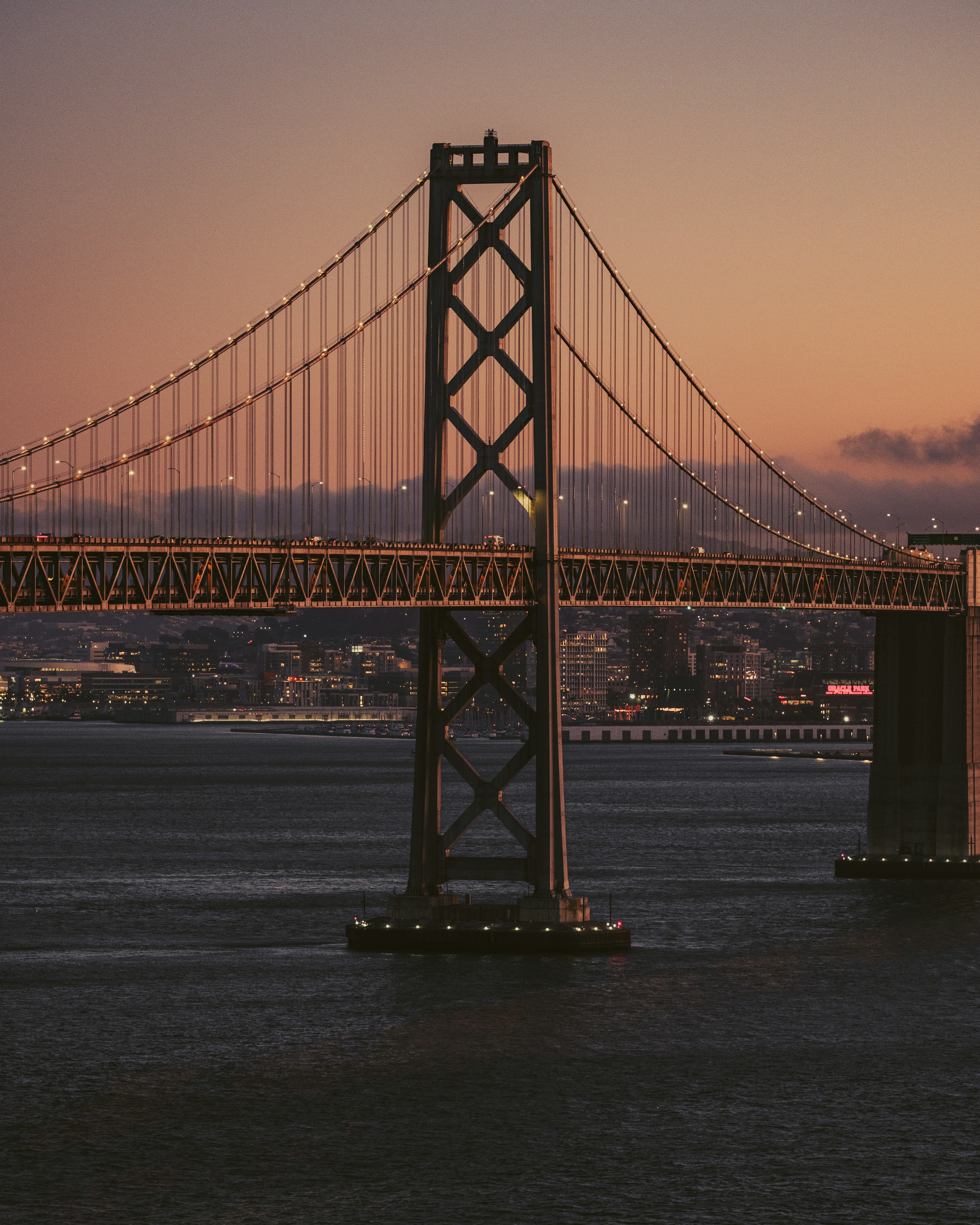 Sunset Span: The silhouette of a suspended bridge over calm waters