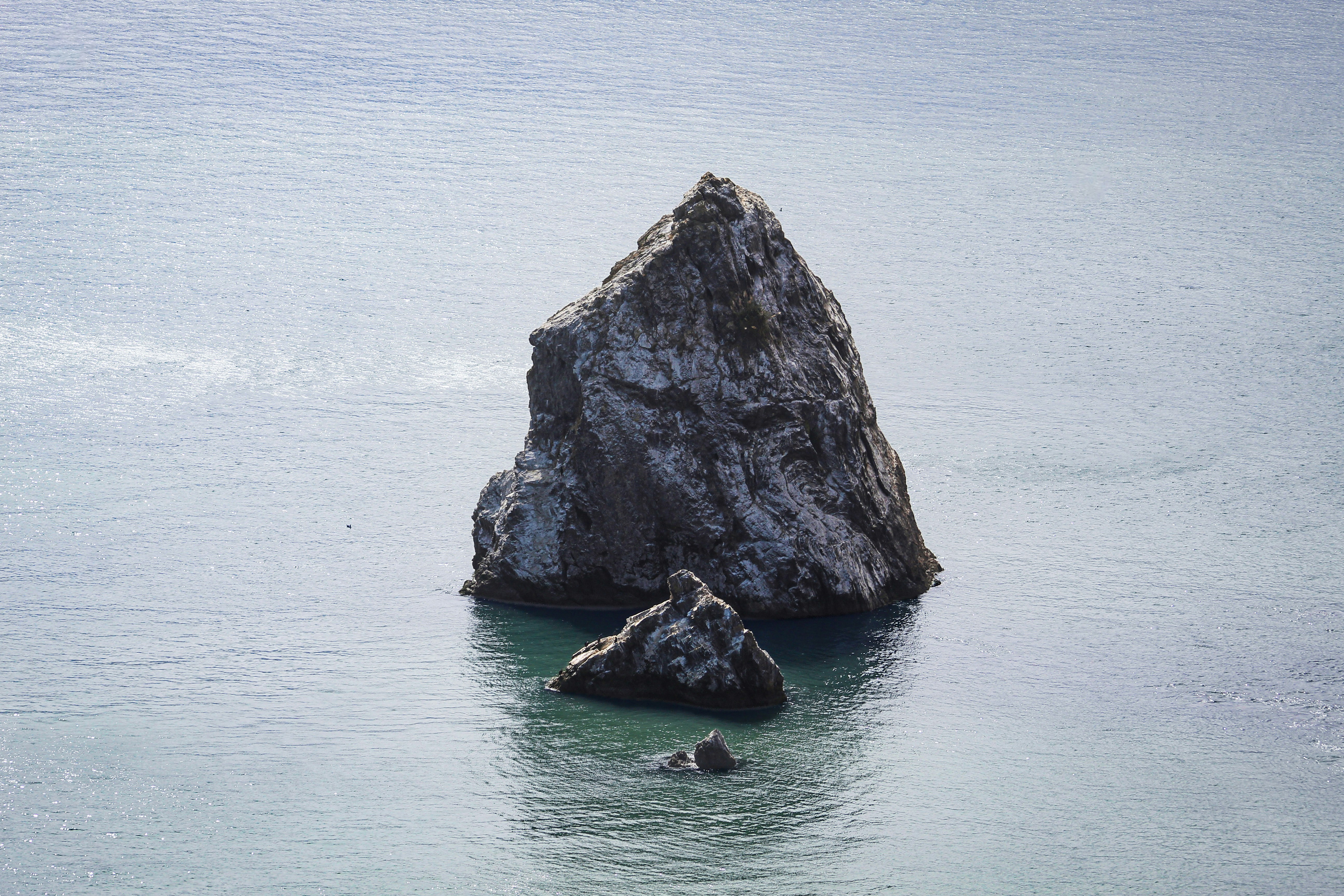 Twin Rocks in Calm Sea: A Quiet Confluence of Shore and Sky