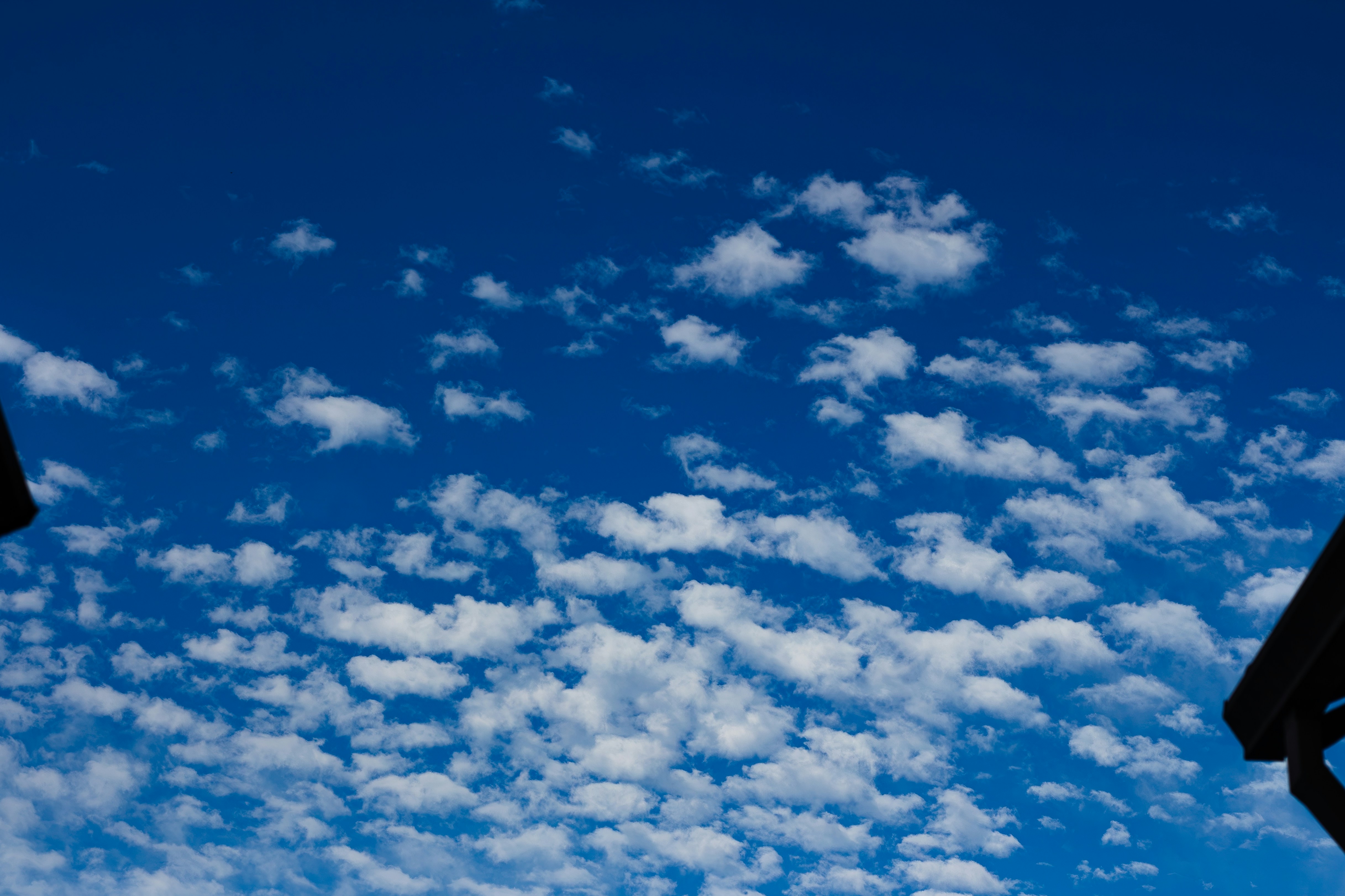 Sky mosaic: cotton-clouds scattered across a deep blue arcade