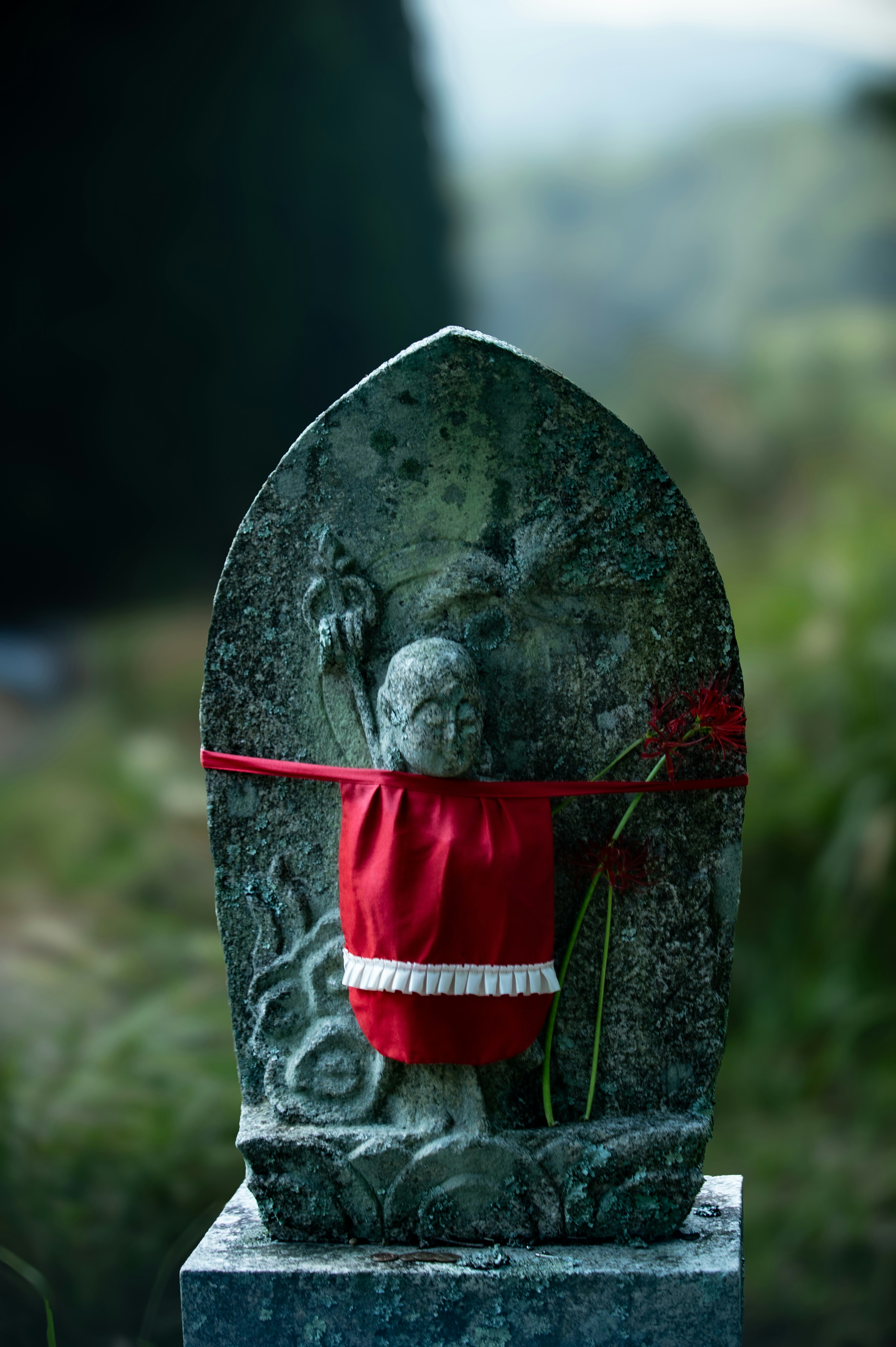 Red-robed Silent Witness: a weathered stone statue bound by a crimson sash