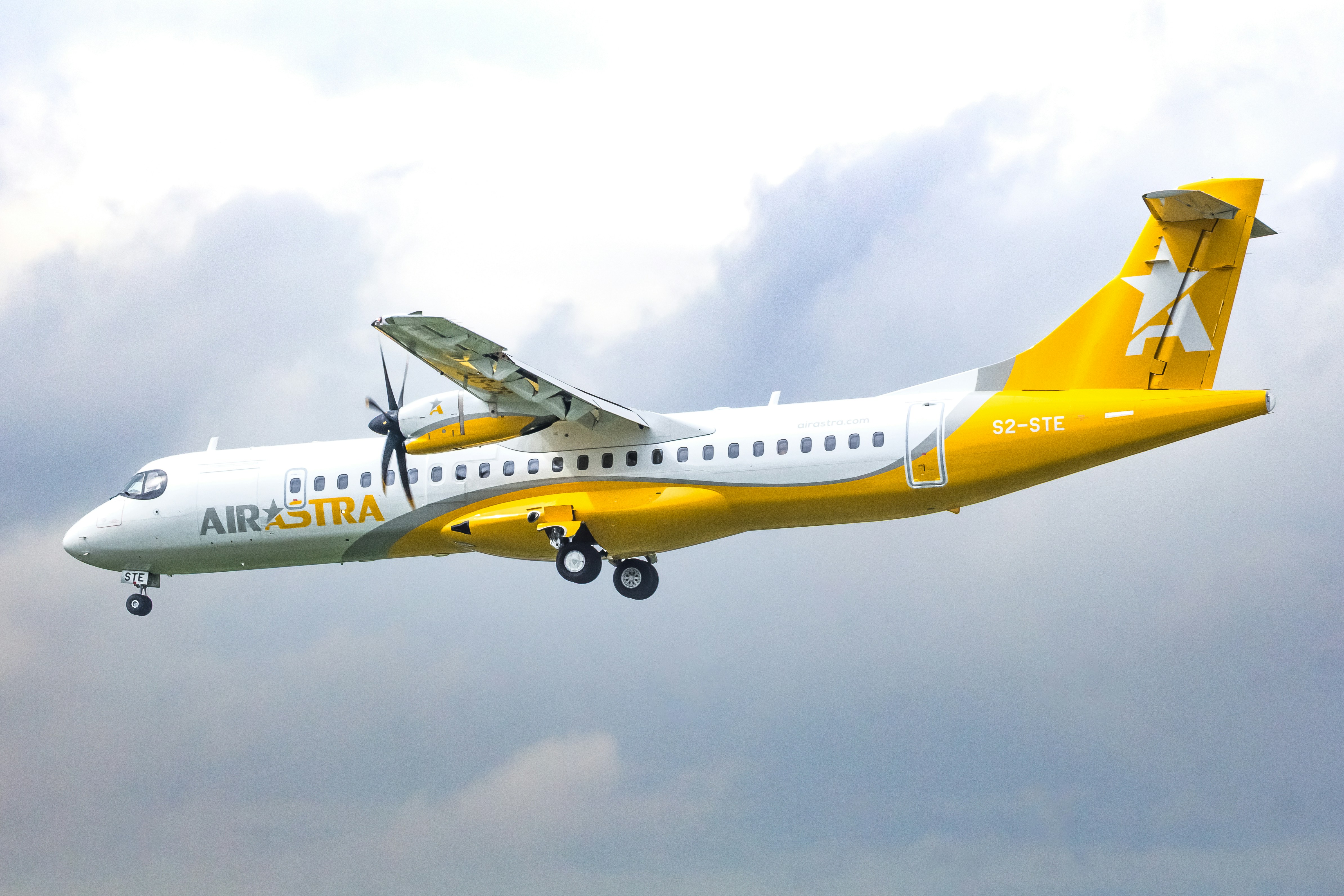 Yellow-tinted regional airliner in ascent against a cloudy sky