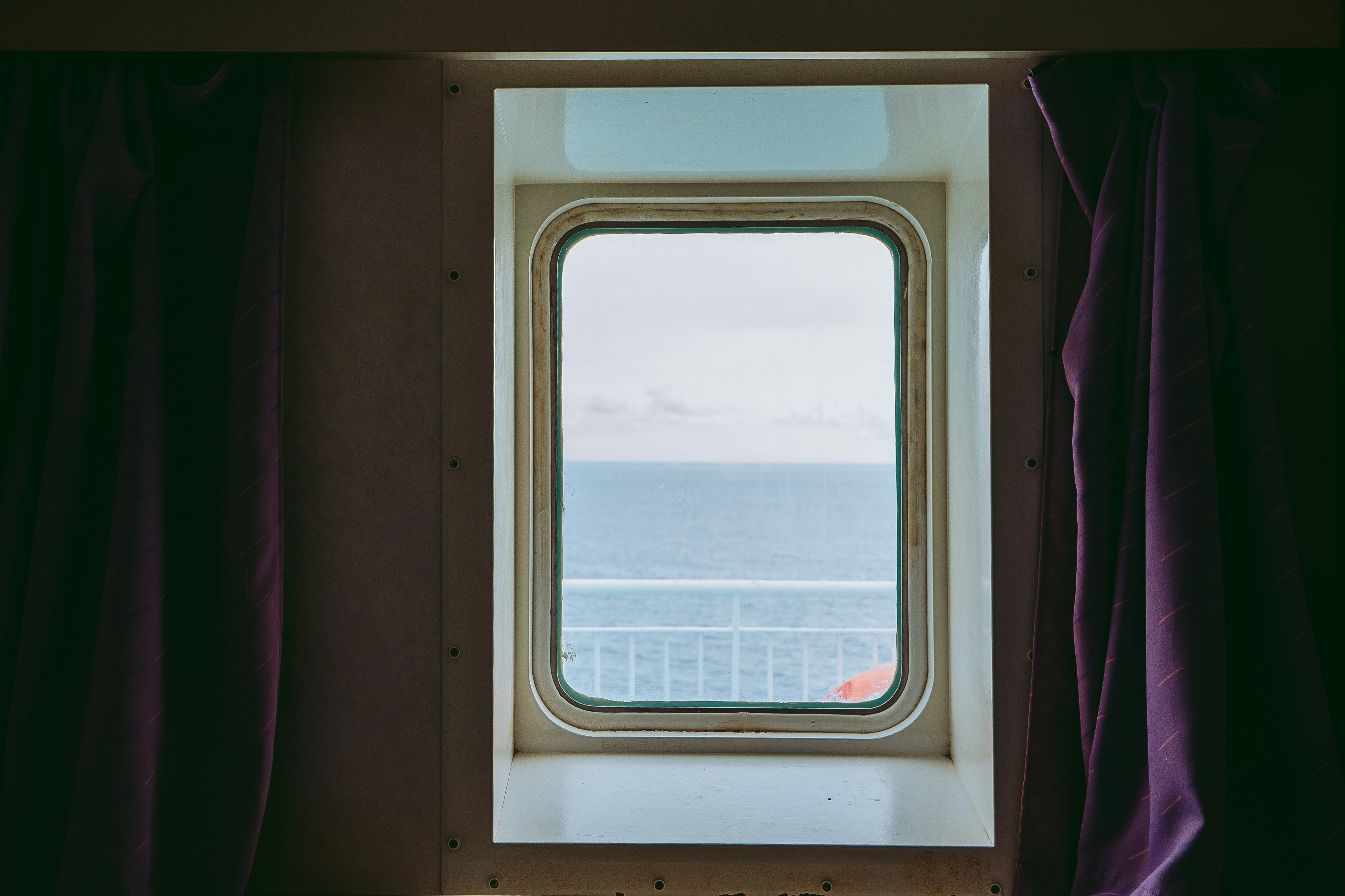 Overwater Window: Sea Light Framed by Narrow Port Hole