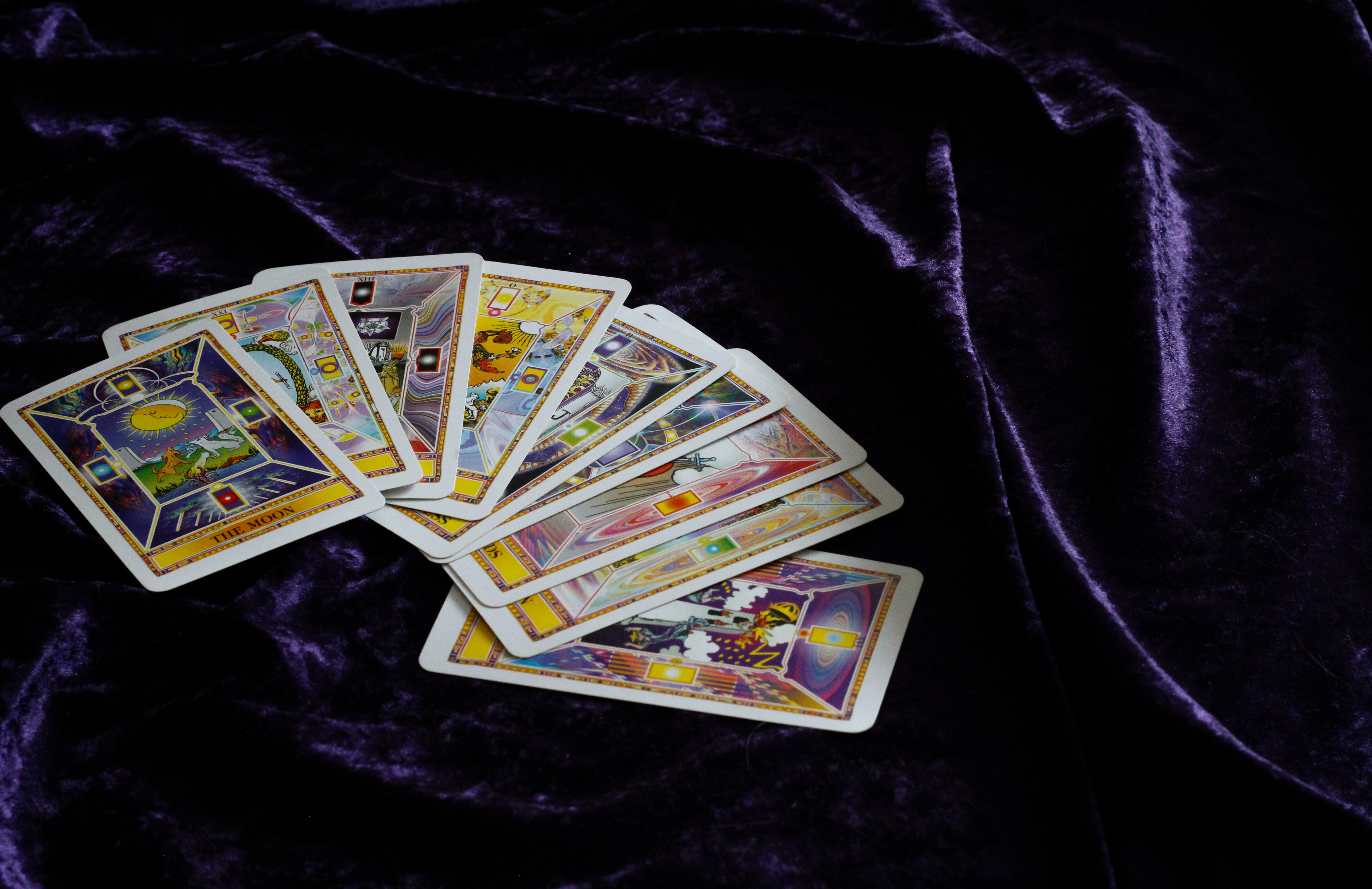 A fan of tarot cards spread out on a dark purple velvet cloth