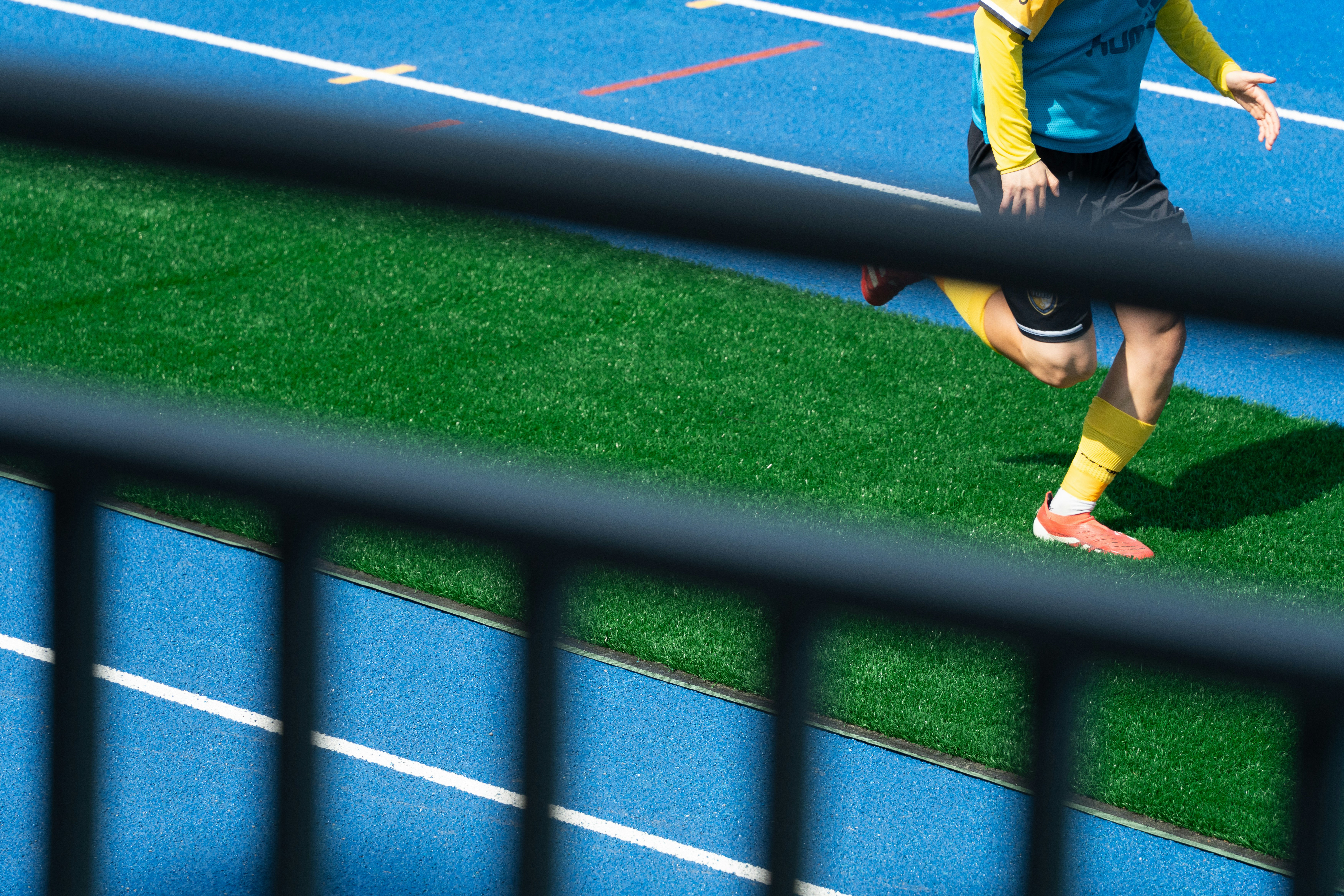 Over the Barrier: A Footballer in Motion on a Neon Track