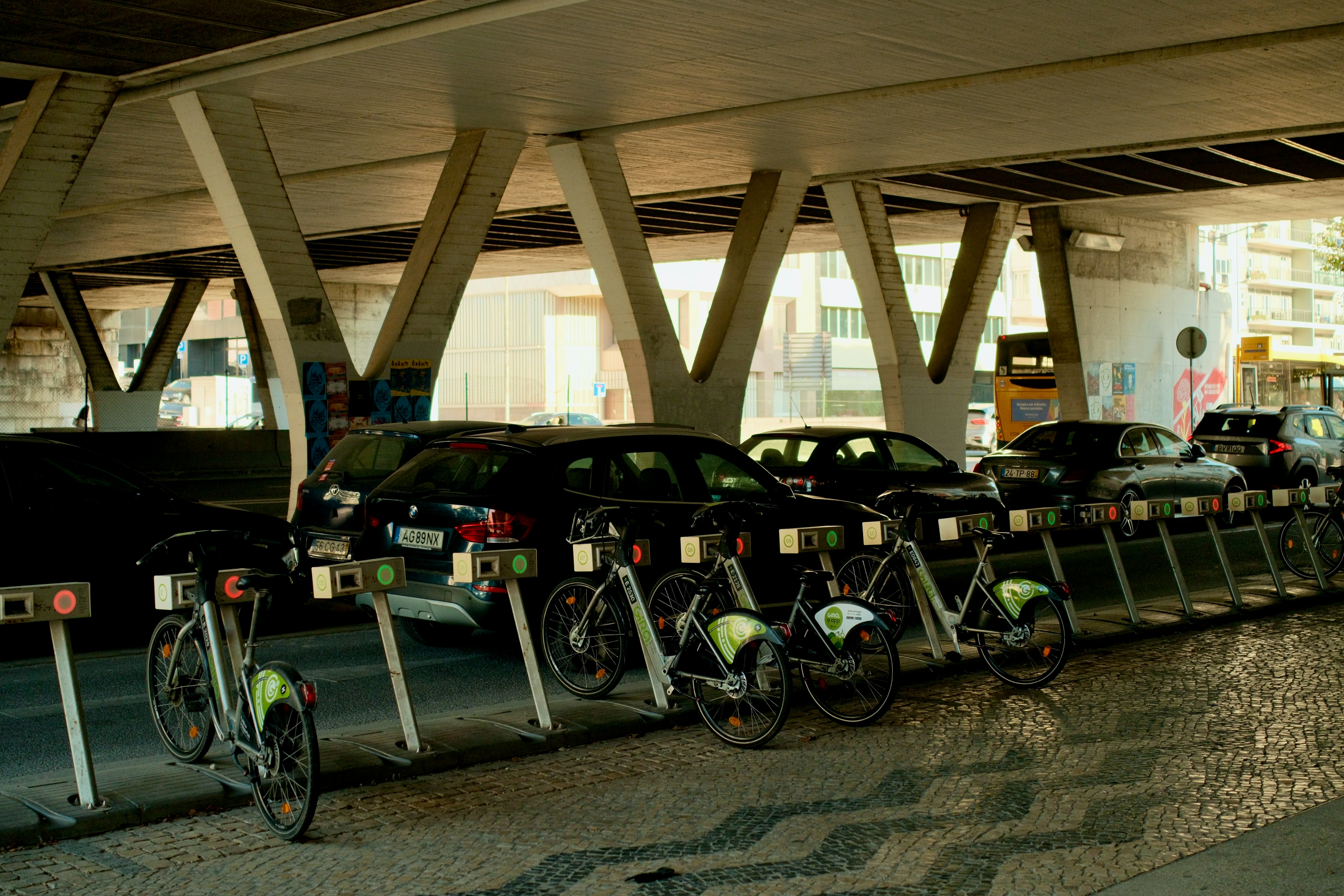 Bicycles and parked cars under a civic overpass
