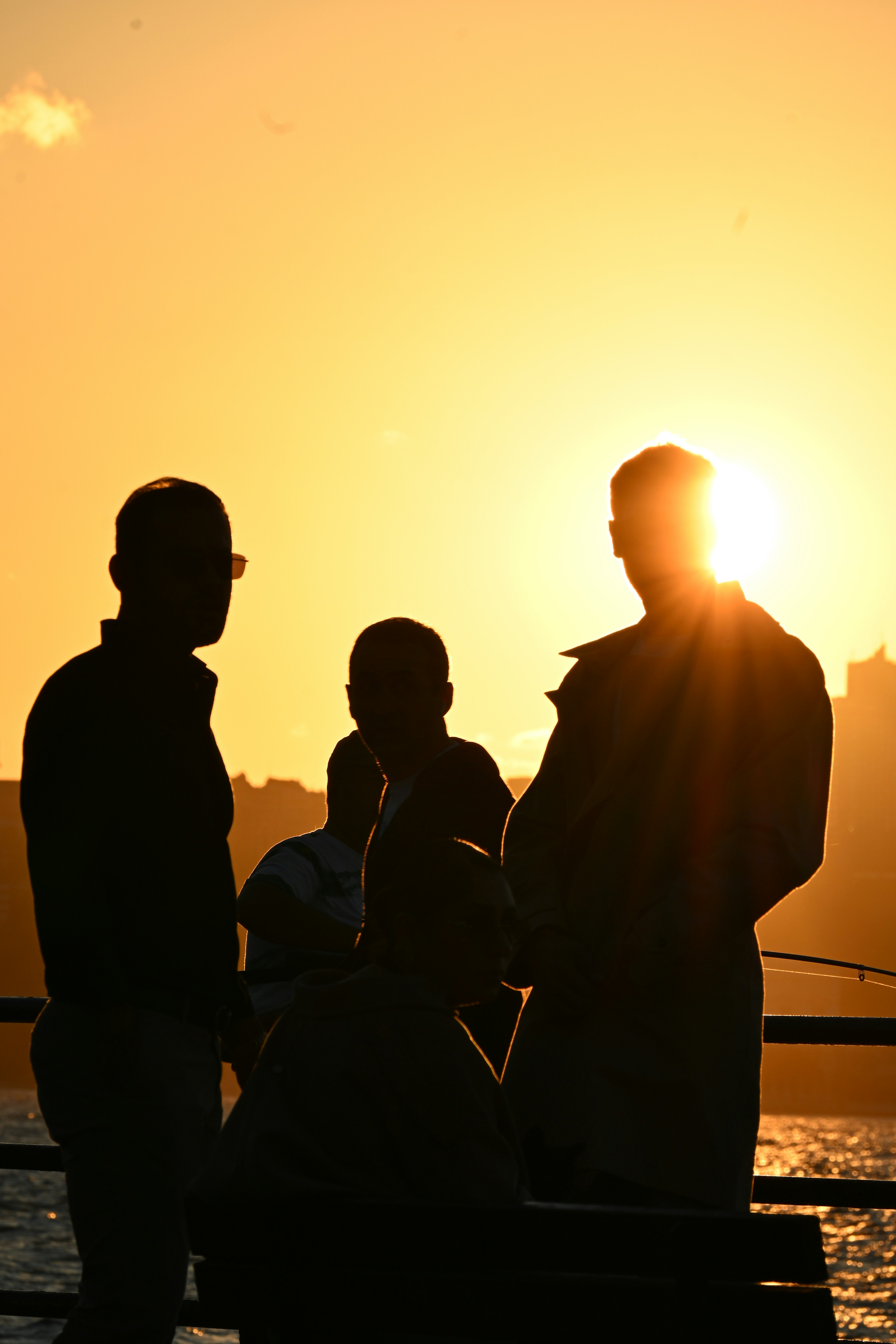 Sunlit silhouettes on the waterfront: a trio at golden hour