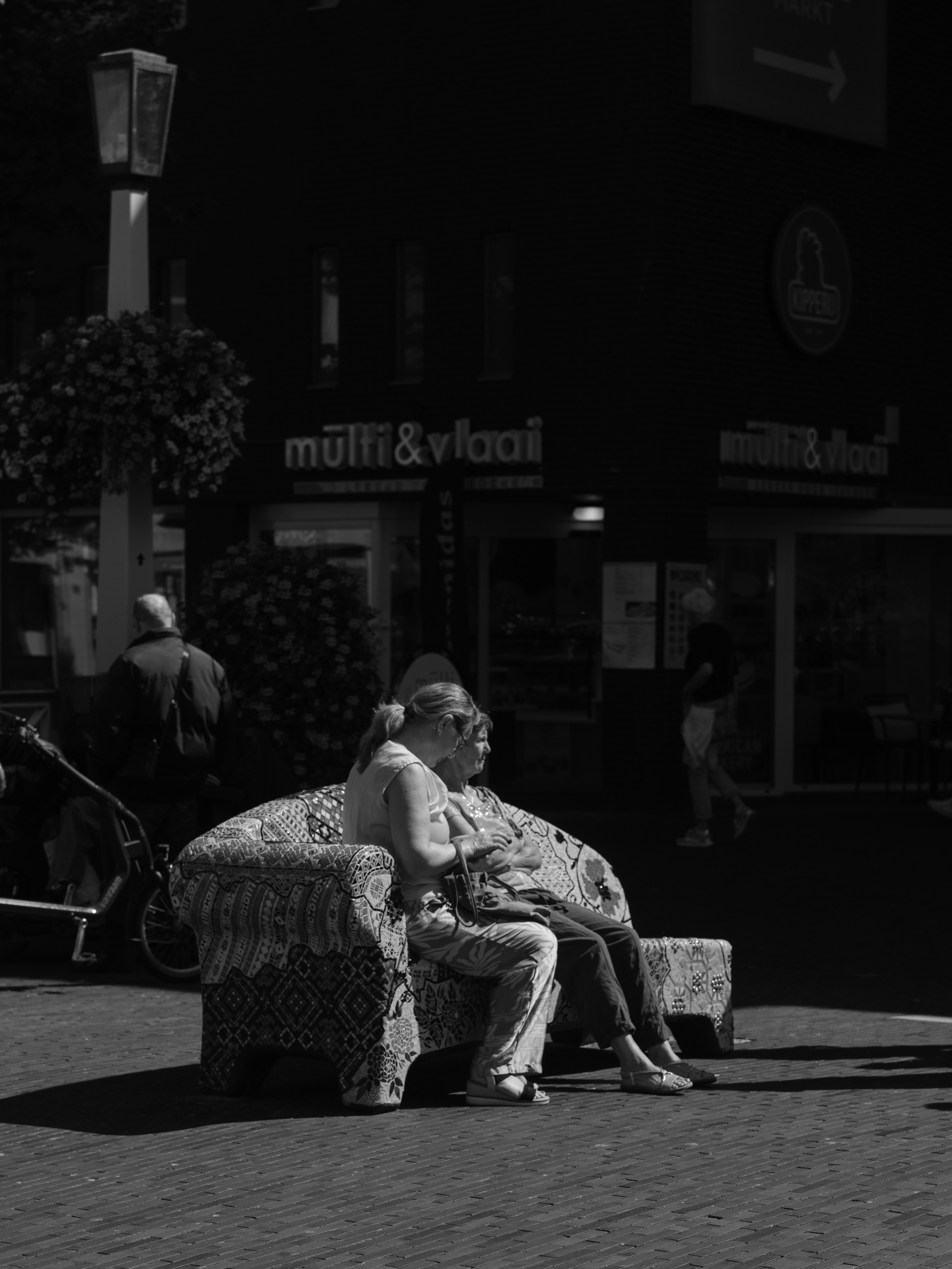 Two Elderly Companions Share a Quiet Moment on a Patterned Street Bench