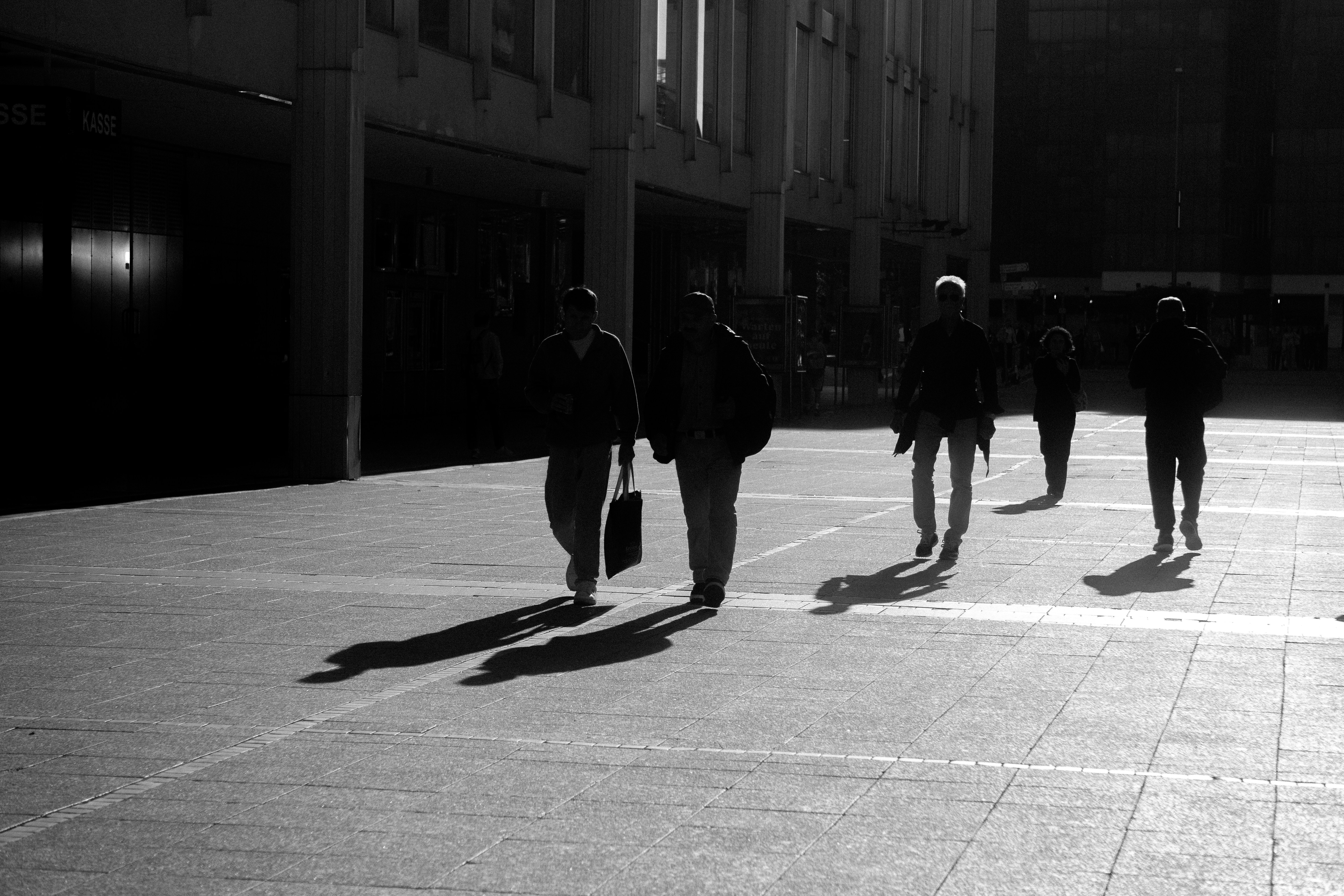 Silent Stride: Shadowed Pedestrians Crossing a Sunlit Plaza