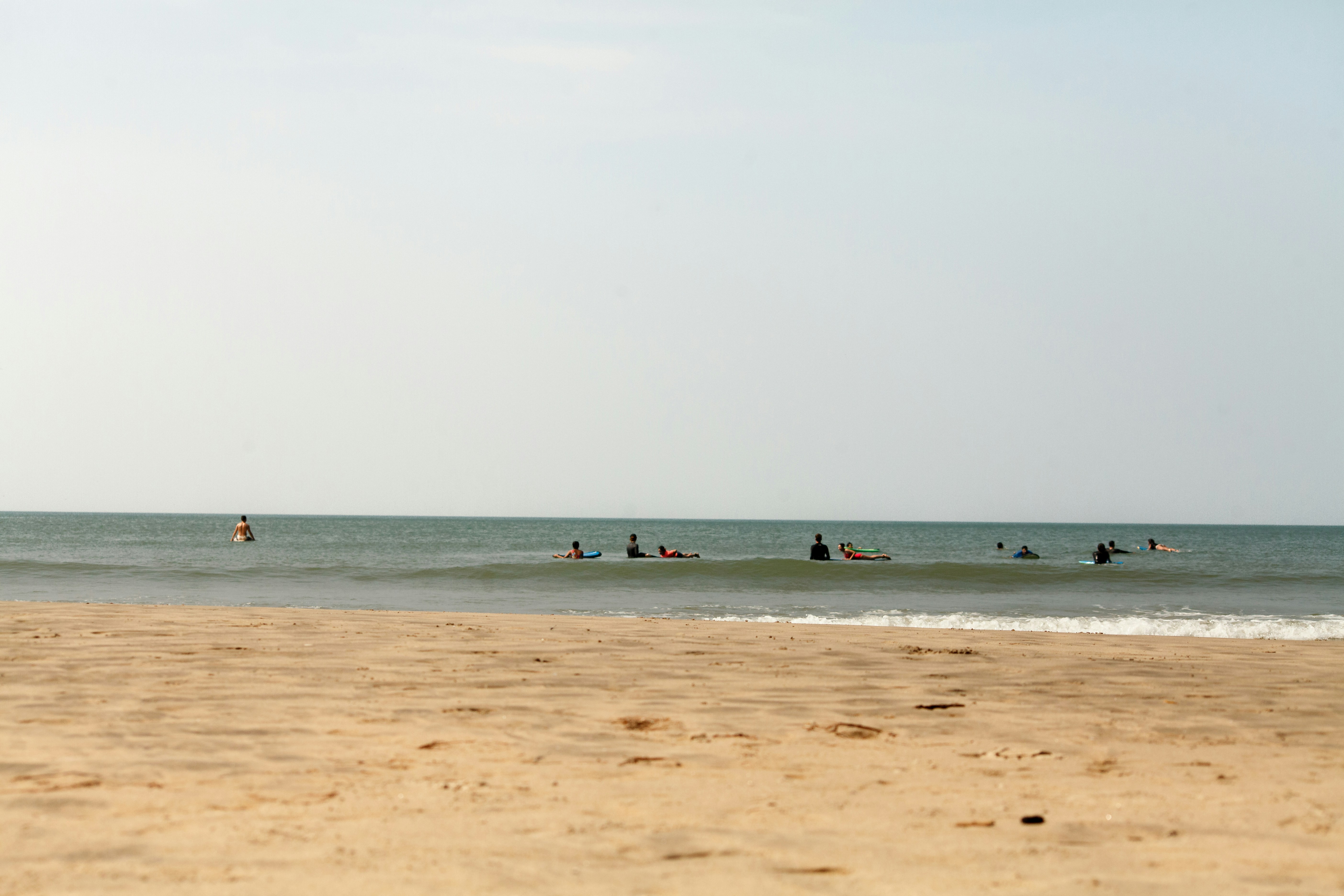 Quiet Lineup: Distant Surfers at a Calm Horizon