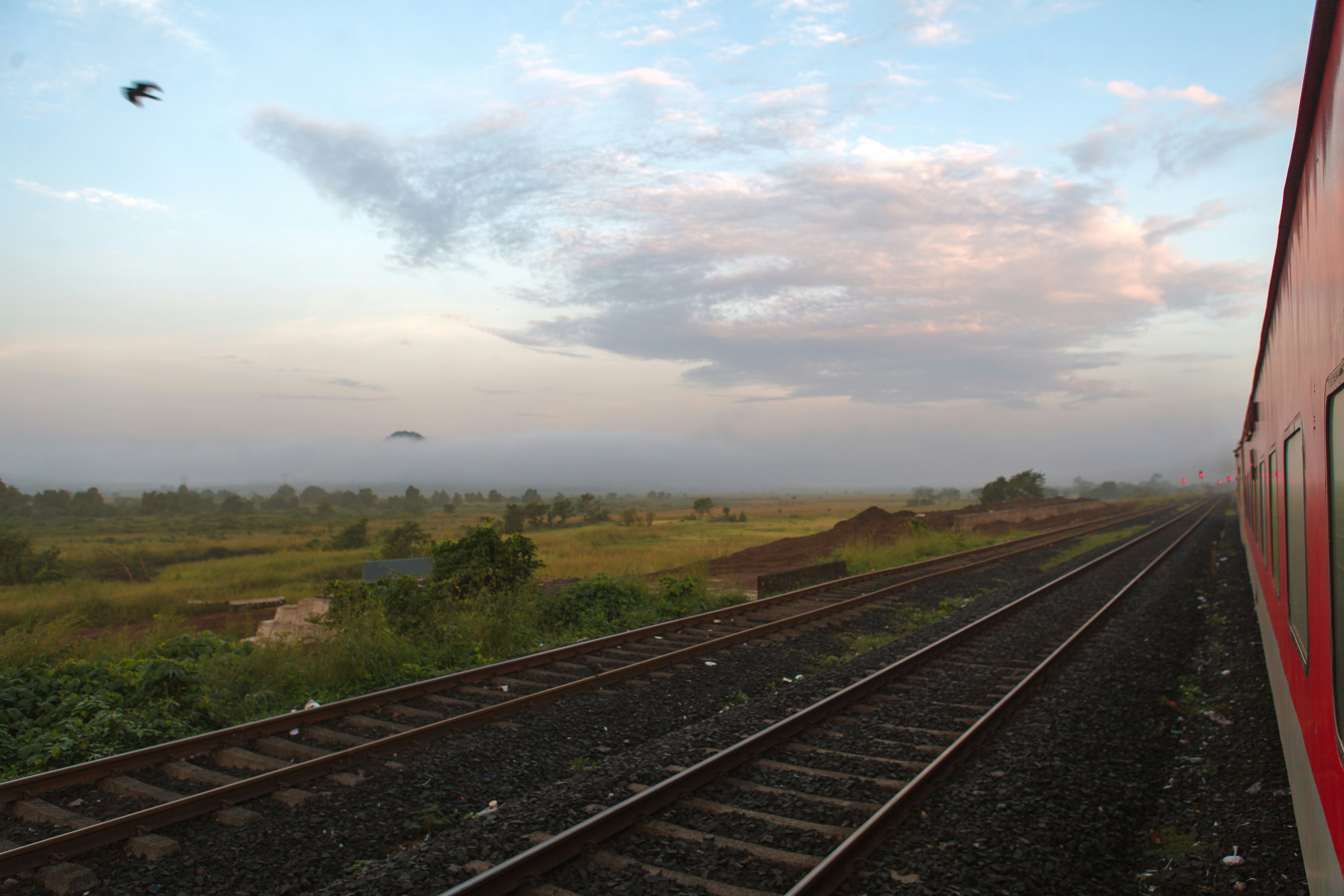 Sunrise along the Rails: Red Carriage at the Edge of the Field
