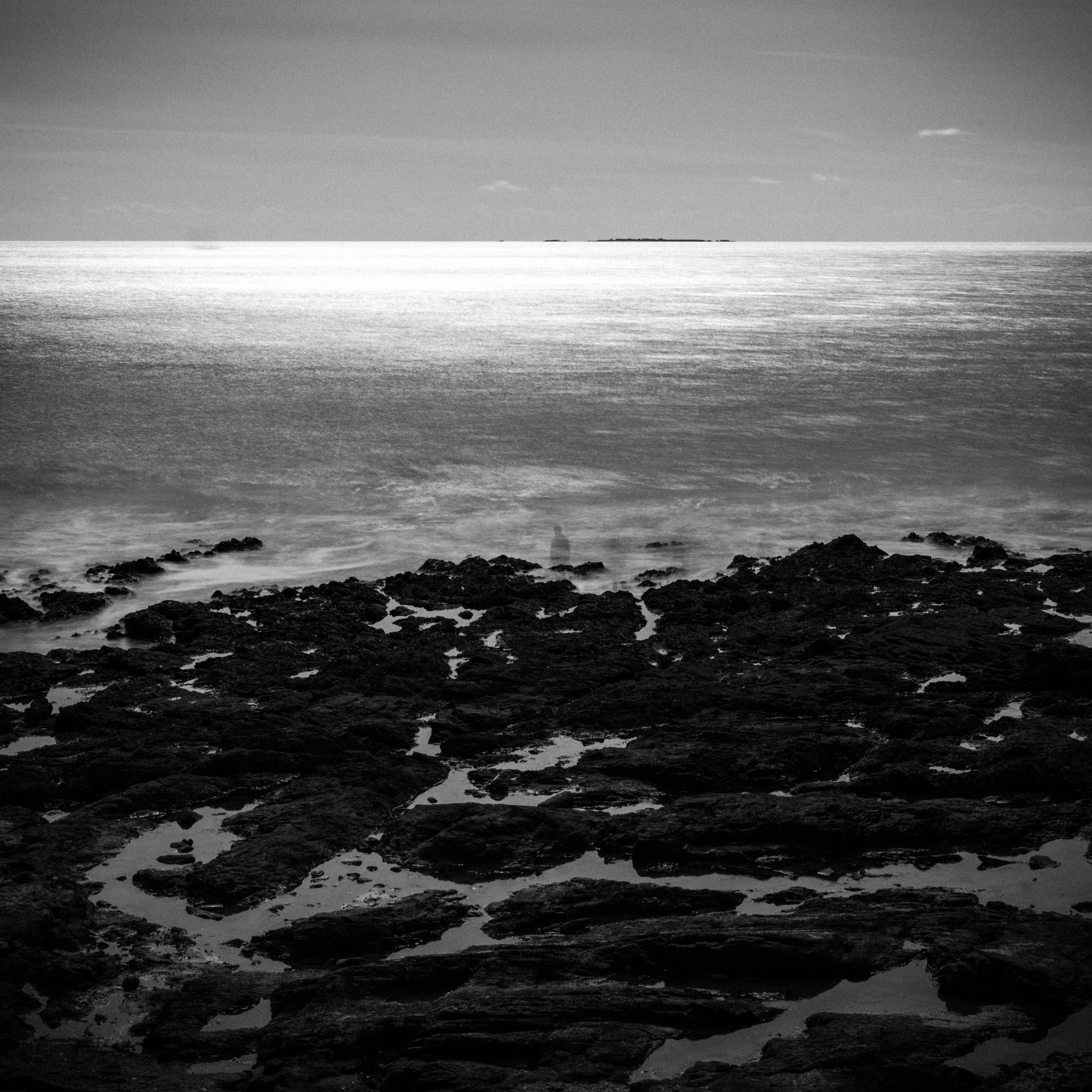 Moonlit Tide: A Quiet Shore of Dark Rocks and Hushed Water